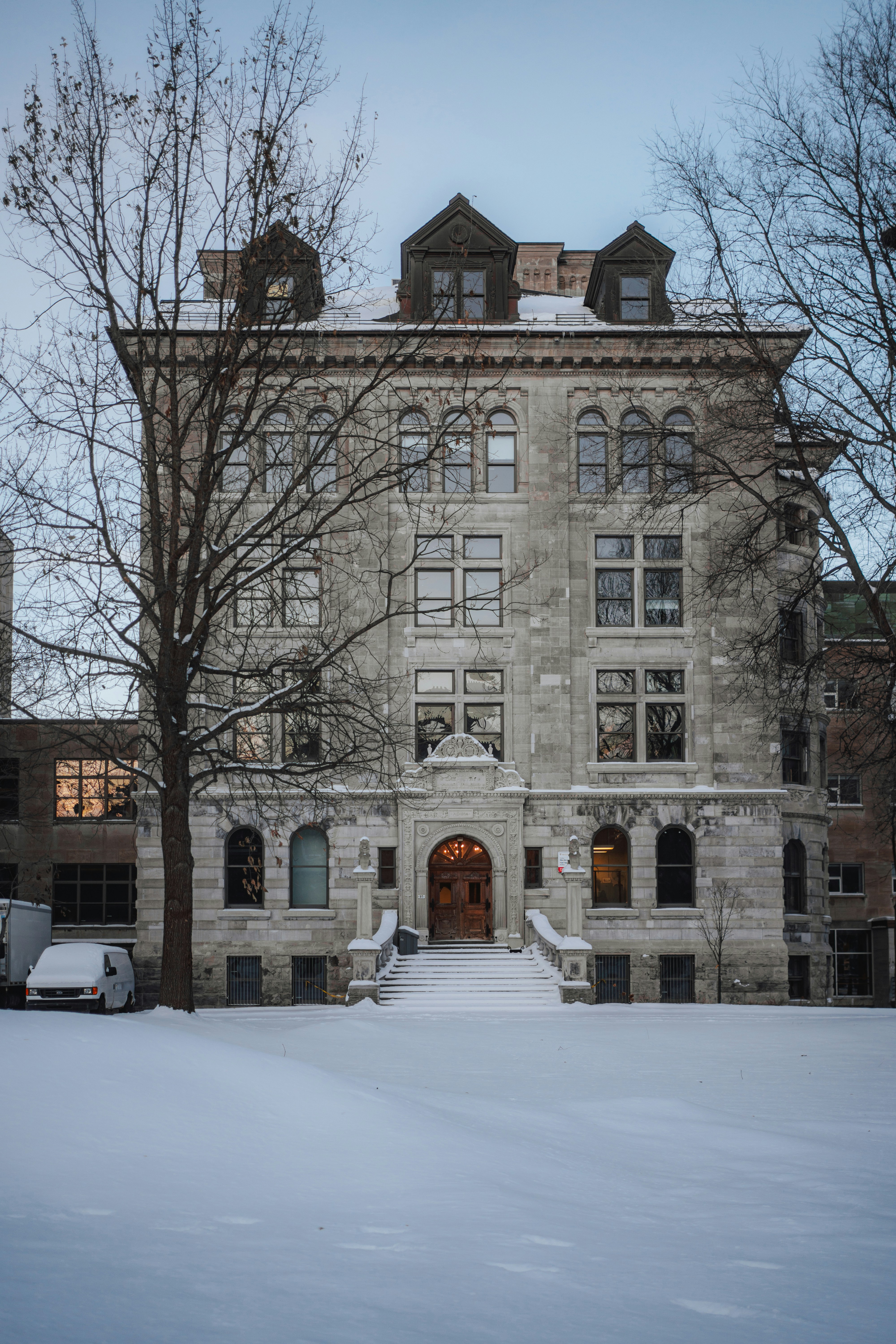 Stone Facade in Winter Quiet: A Symmetrical Campus Building Framed by Bare Trees