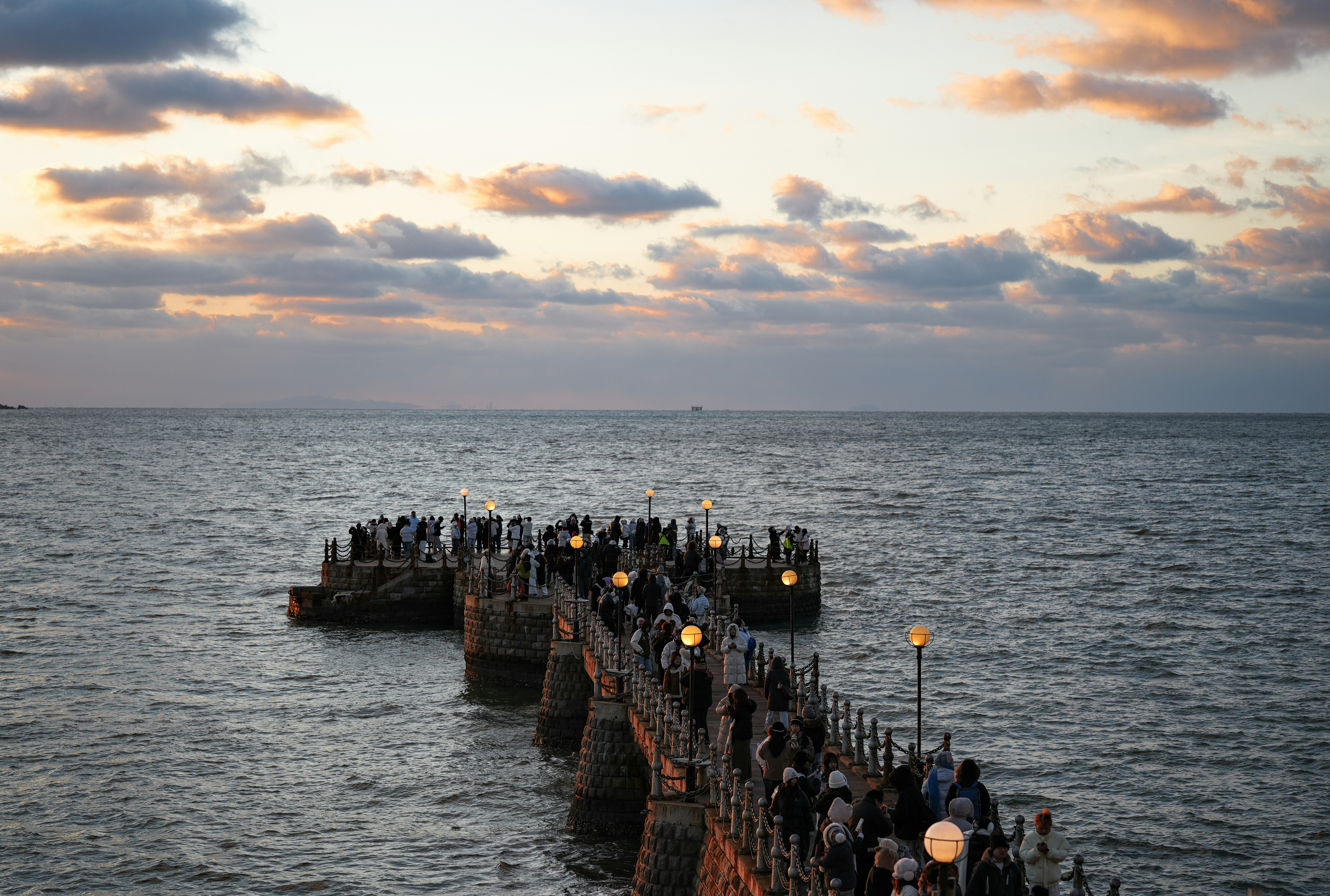 Dusk At The Pier: A Crowded Walkway Into the Sea