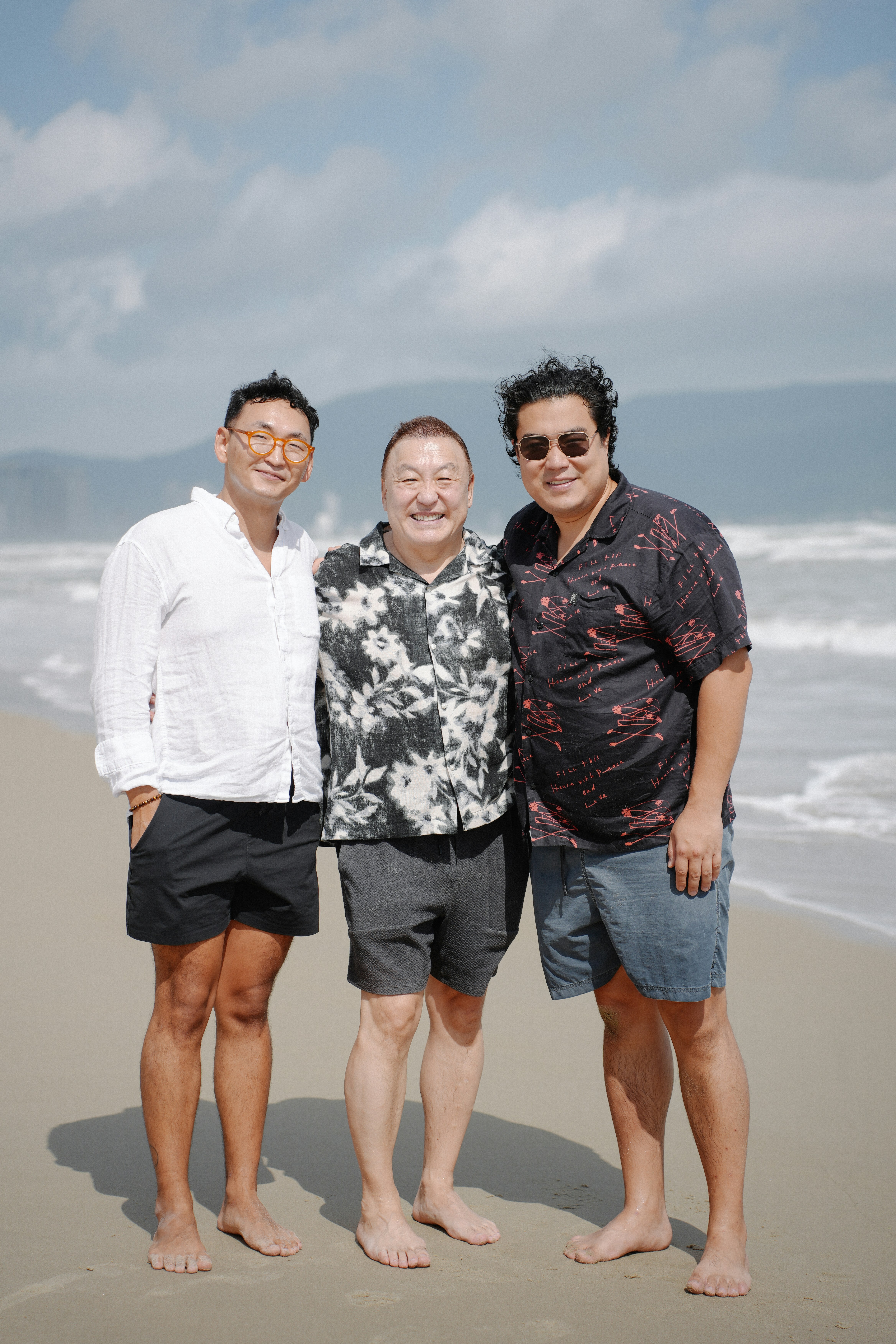Coastal Trio: Three Friends Standing Close on the Sunlit Beach