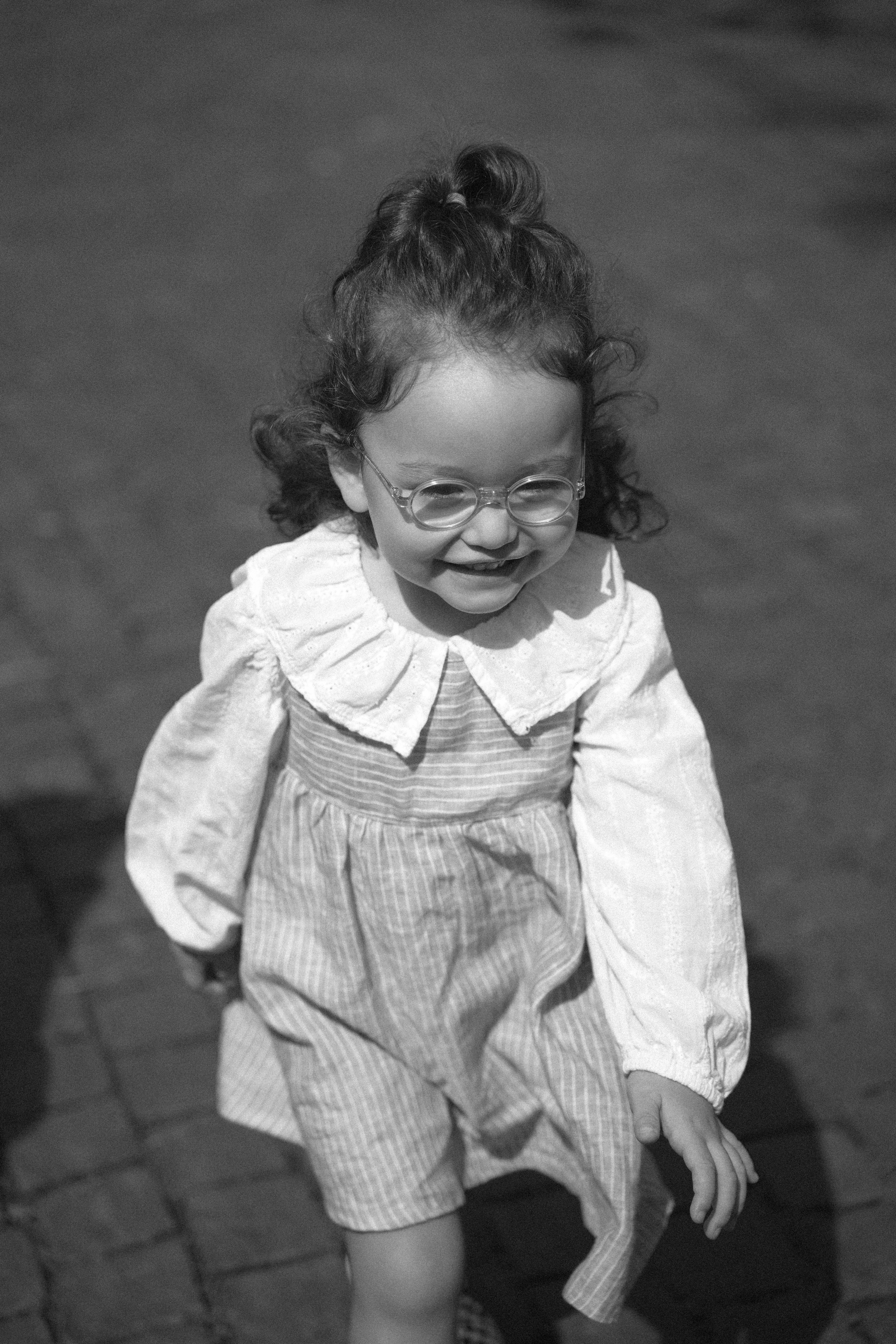 A young girl with glasses smiles while walking.