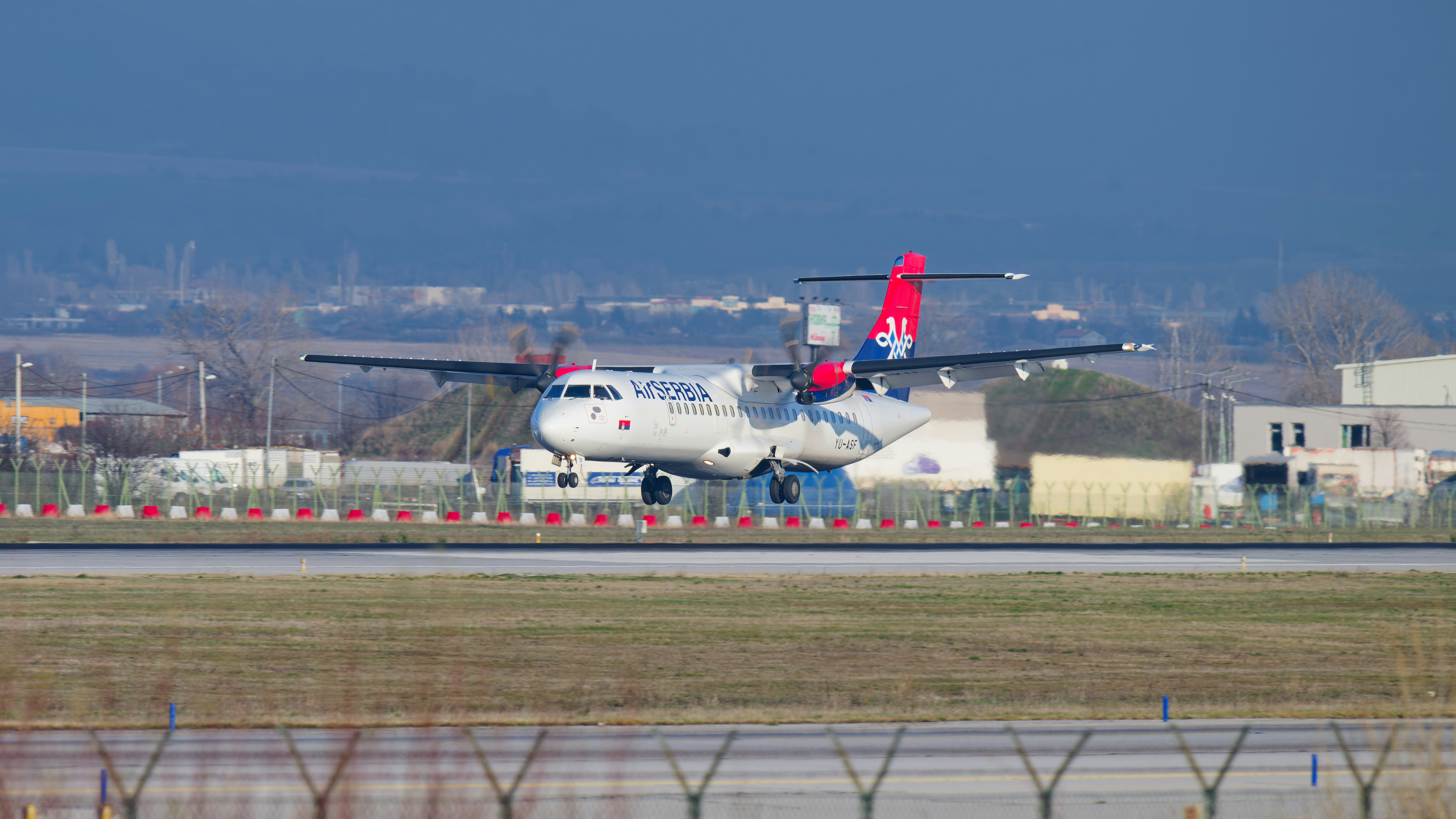 Red-tailed turboprop on taxiway under calm sky