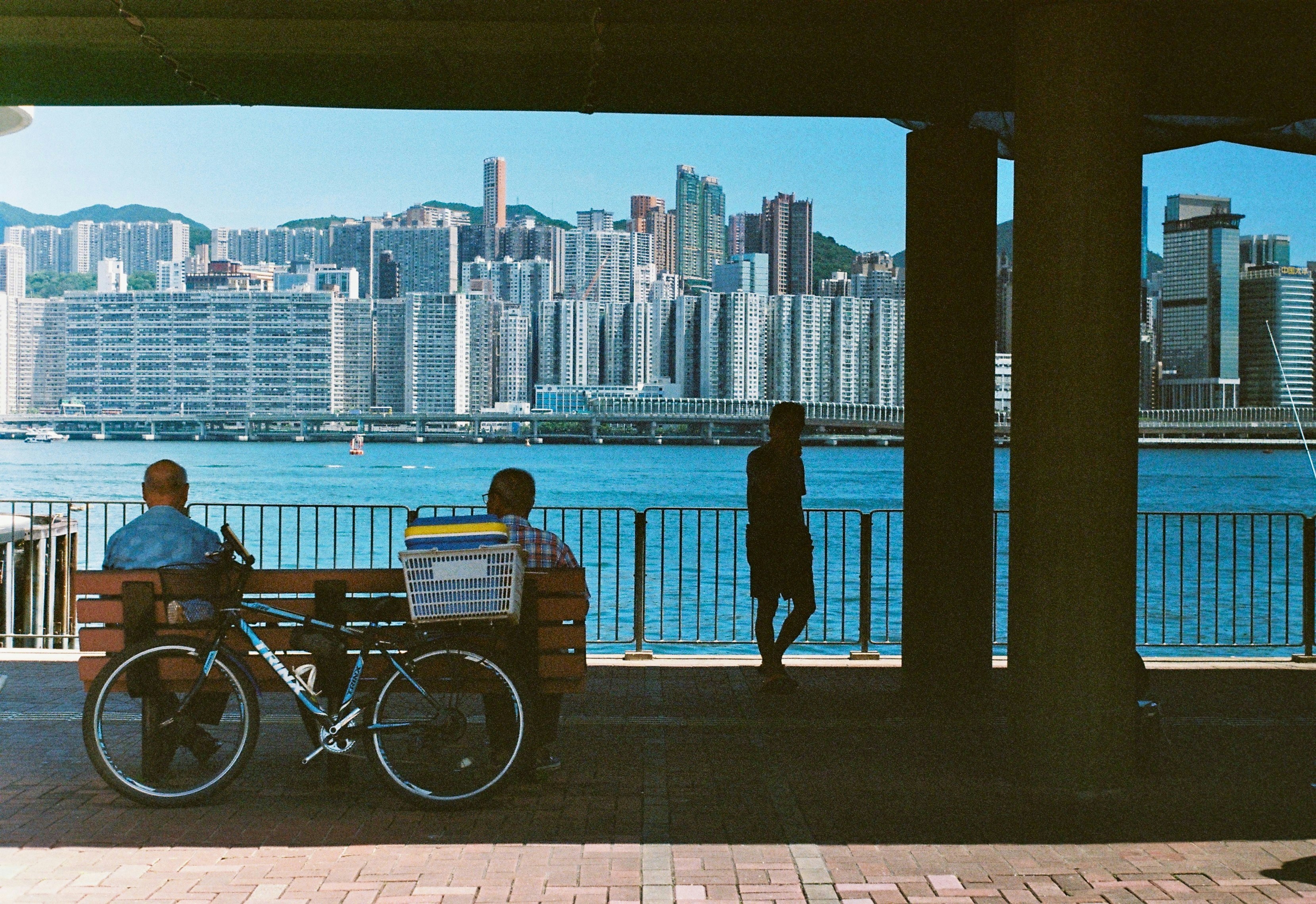 Harbor Vista: Bicycles, Pedestrian, and Skyline through a Waterfront Walkway