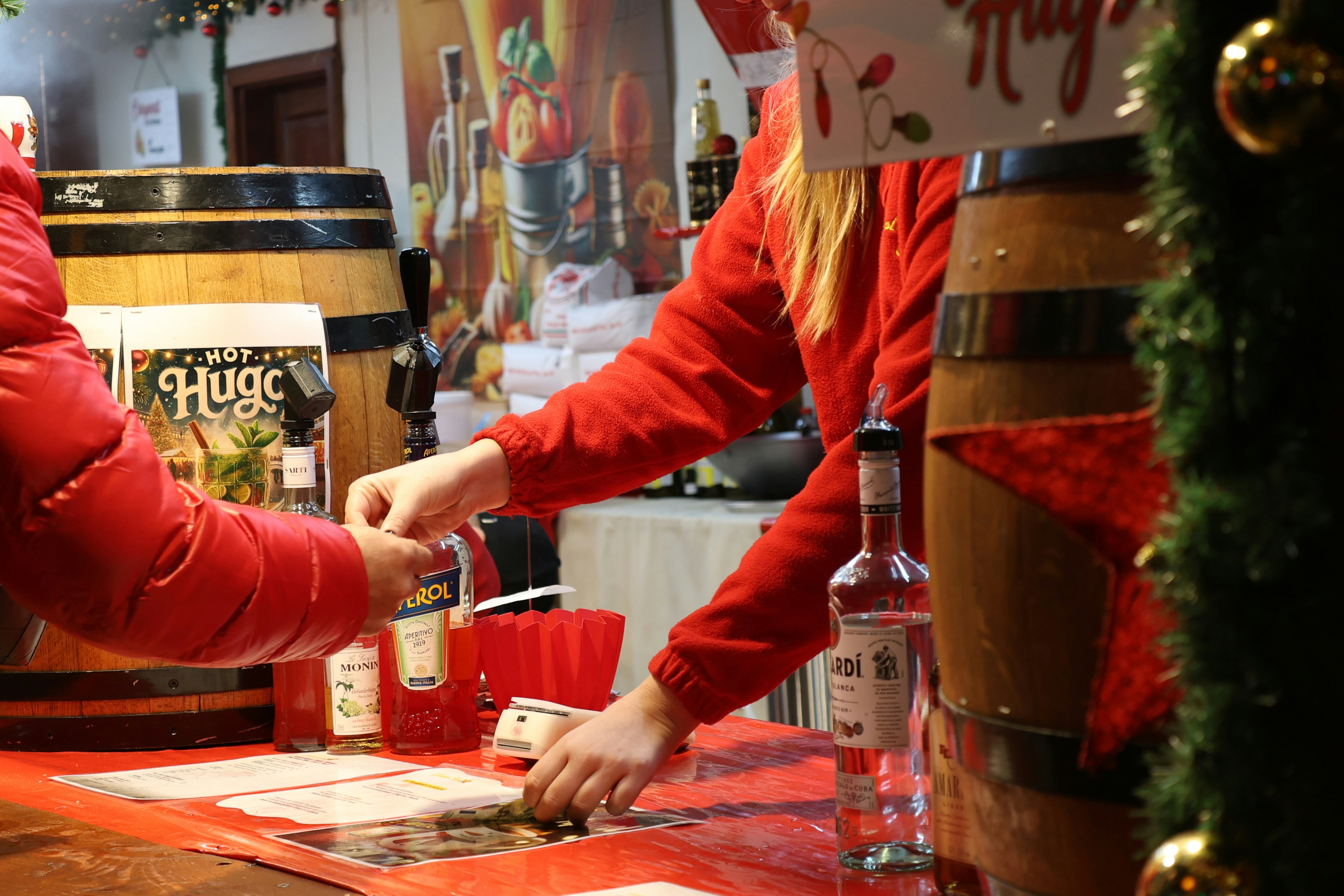 Red-coated handoff at a festive beverage stall
