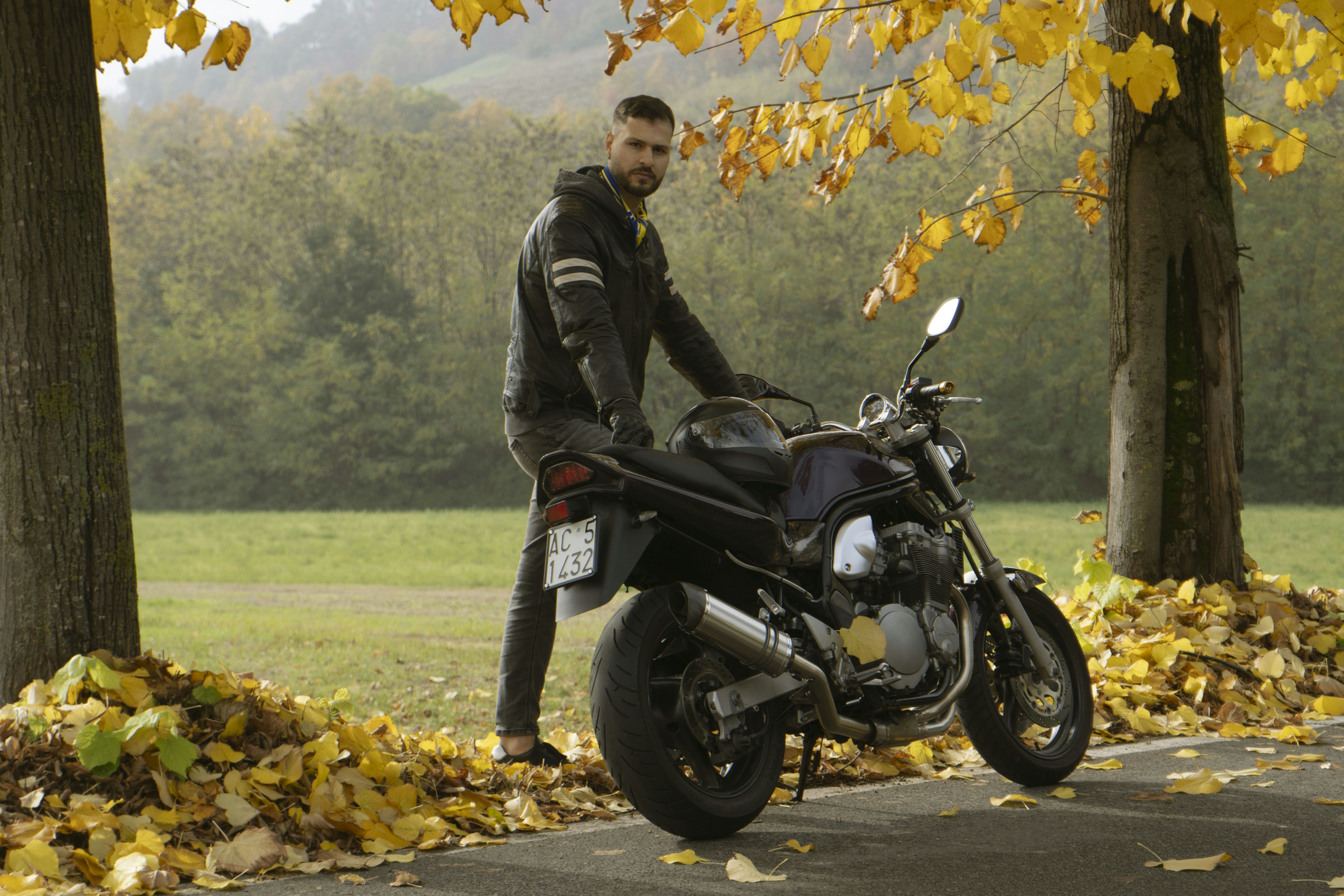 Autumn Ride: Rider with a Matte Black Motorcycle Beneath Golden Leaves