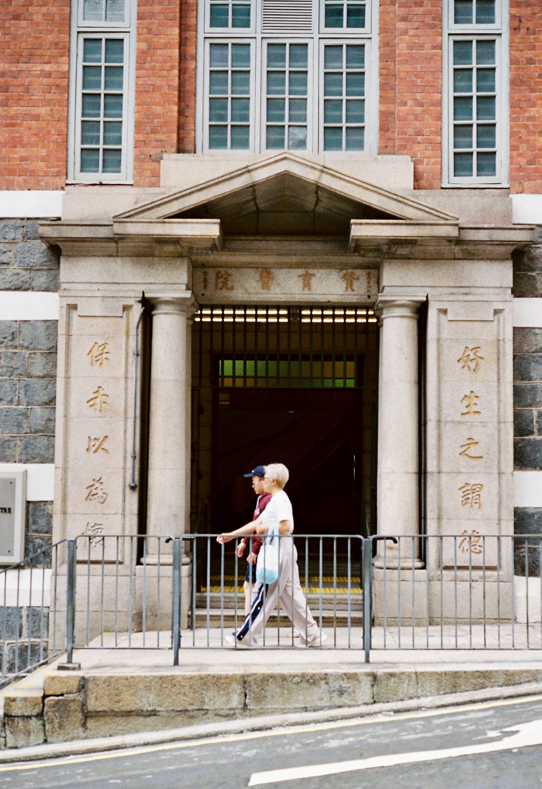 Passing Through a Quiet Archive: Tourists Stepping by a Historic Entrance