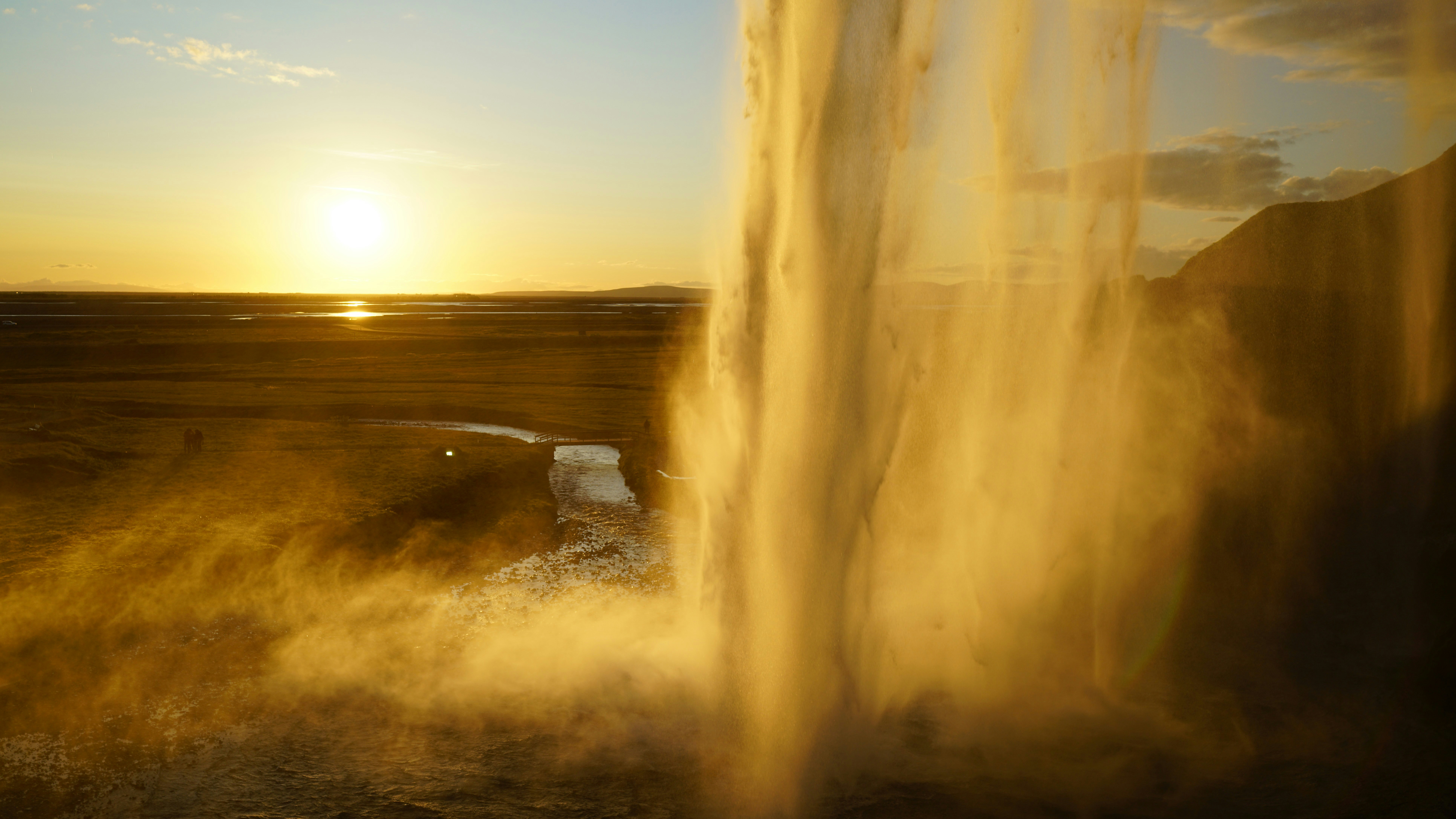 Golden sunset over a misty waterfall landscape