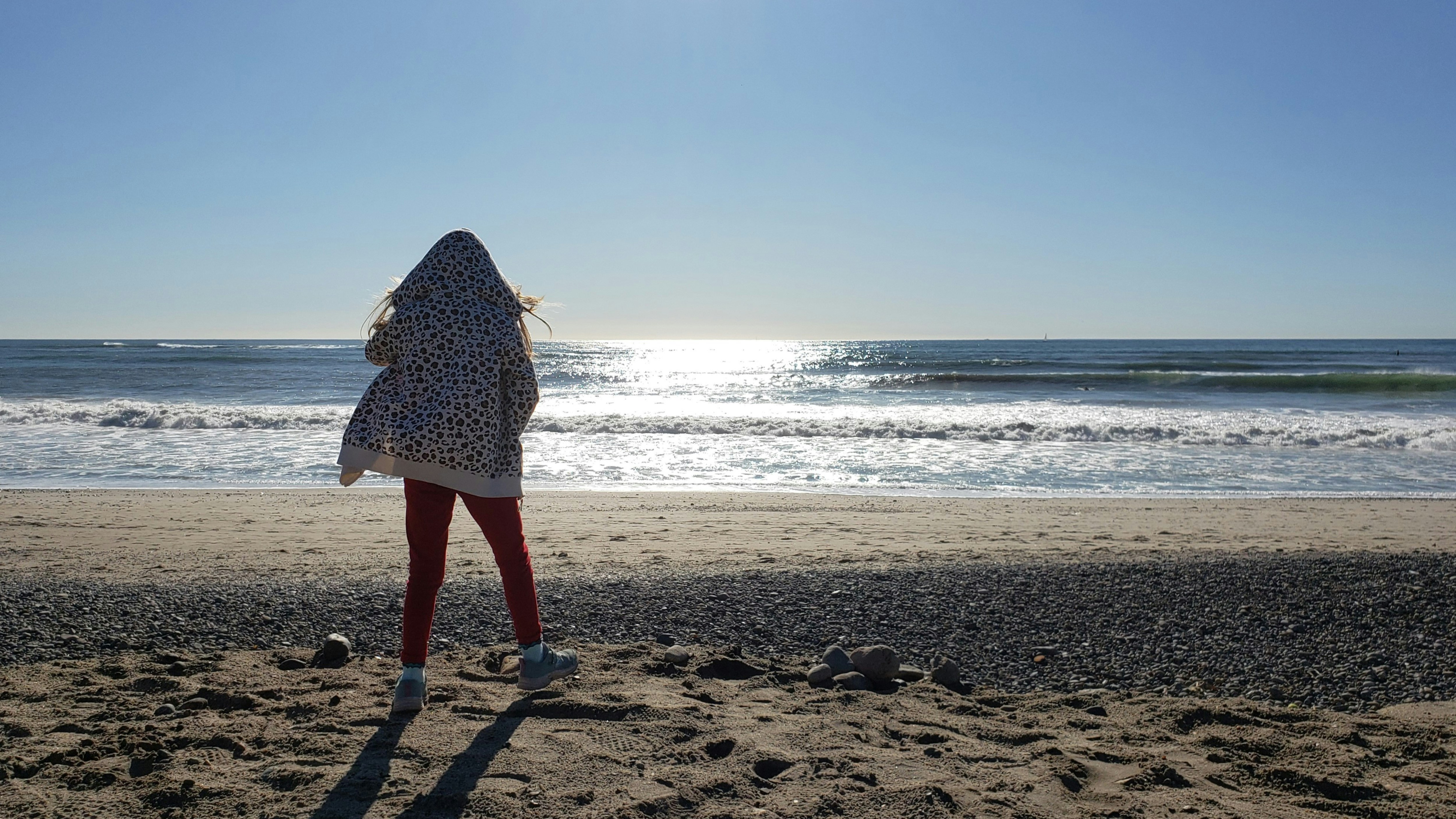 Silhouette on the Shore: A Child’s Shadow dances with the Sea