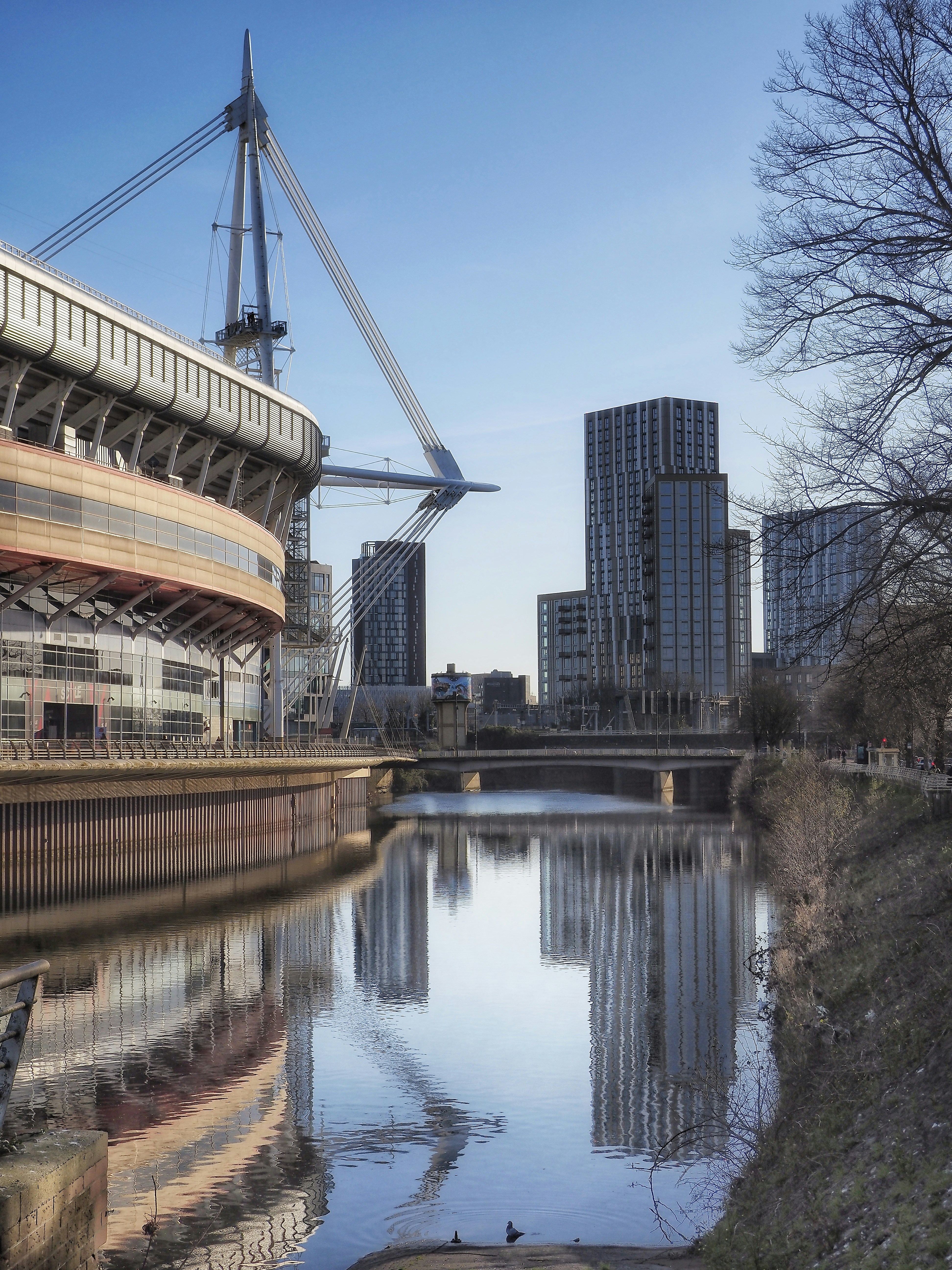 Bridge-tower reflections over a calm urban canal