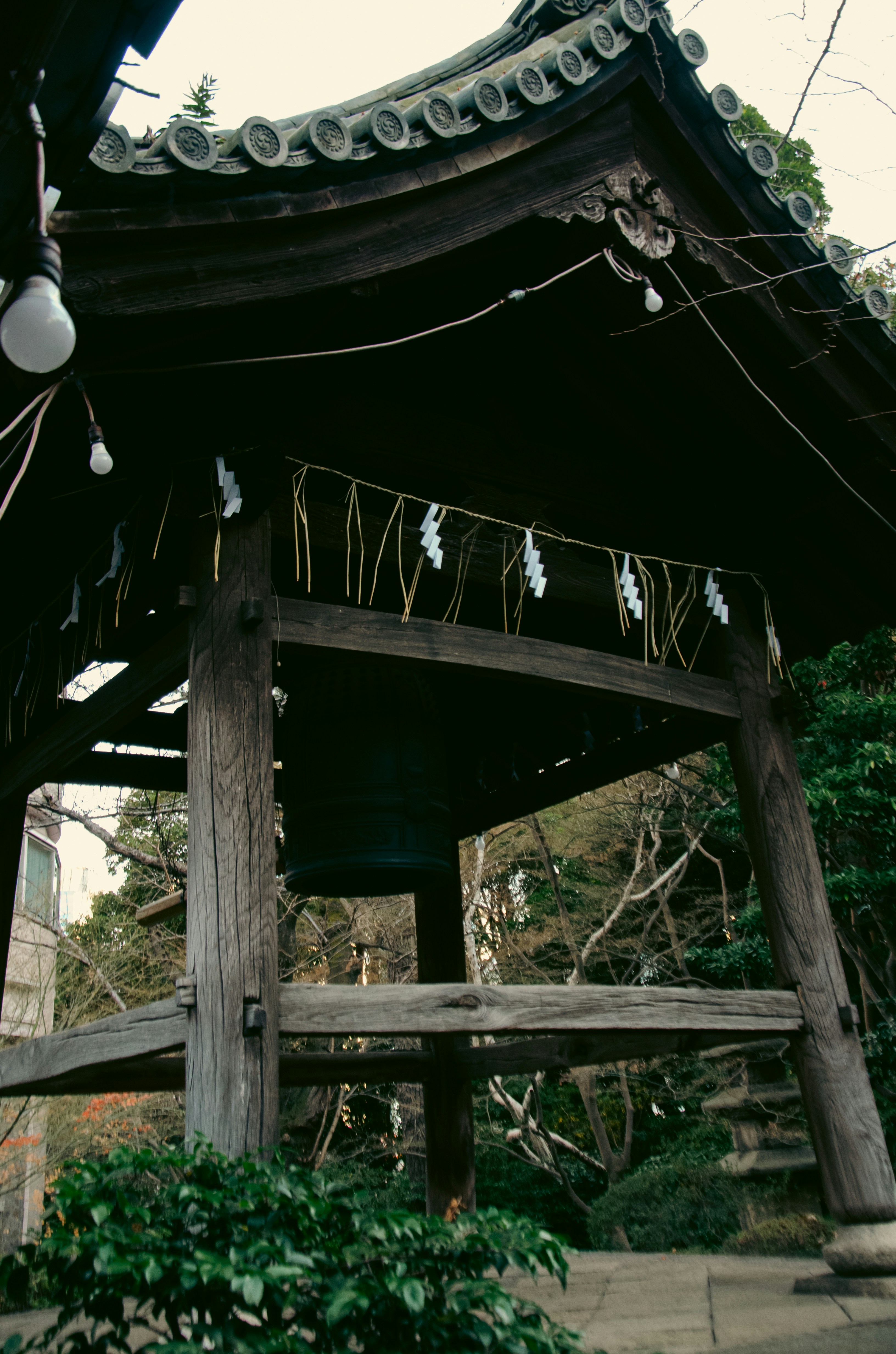 Temple Bell under Ornate Eaves: Weathered Wood and Shimenawa