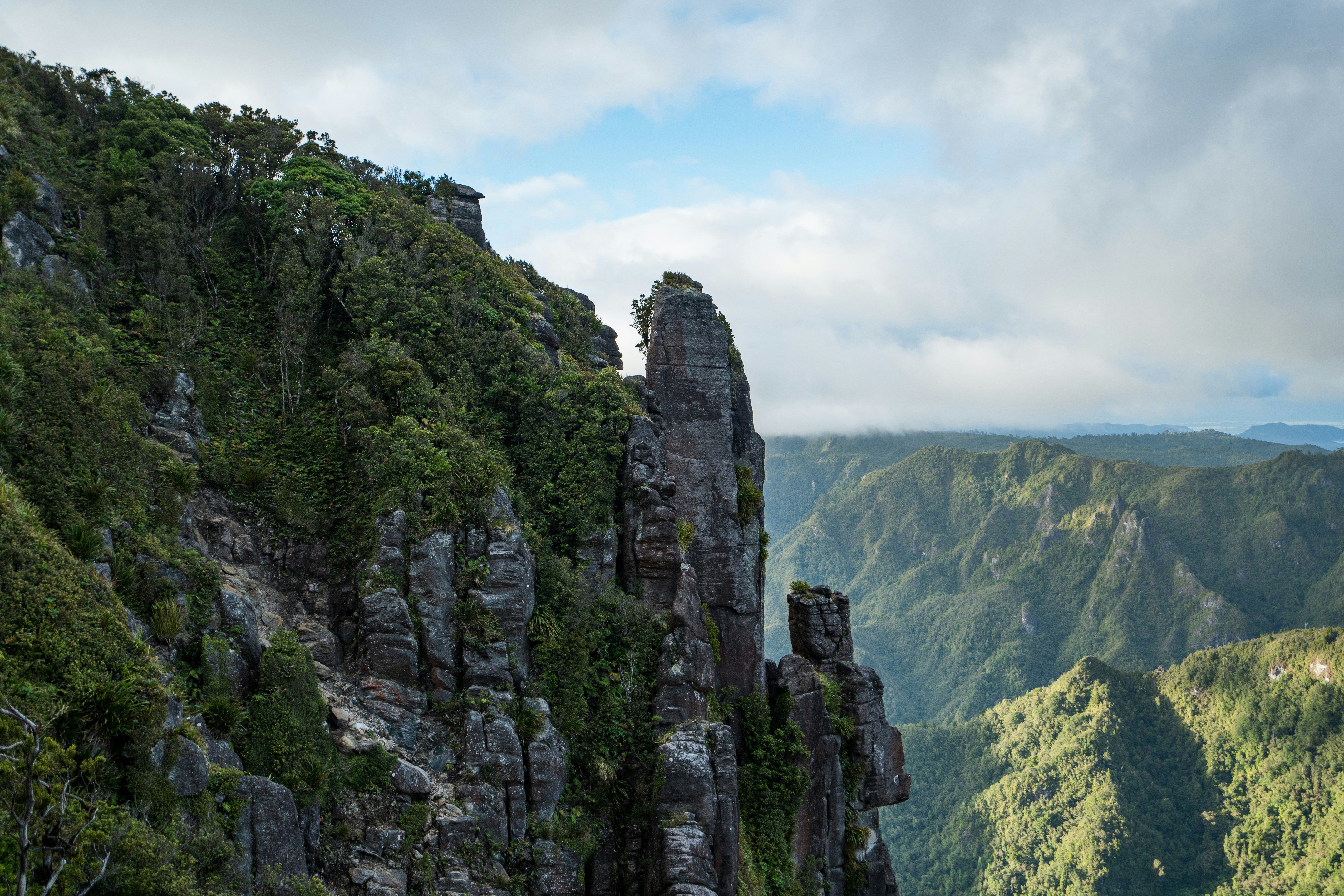 Jagged rock formations covered in green foliage overlooking valleys