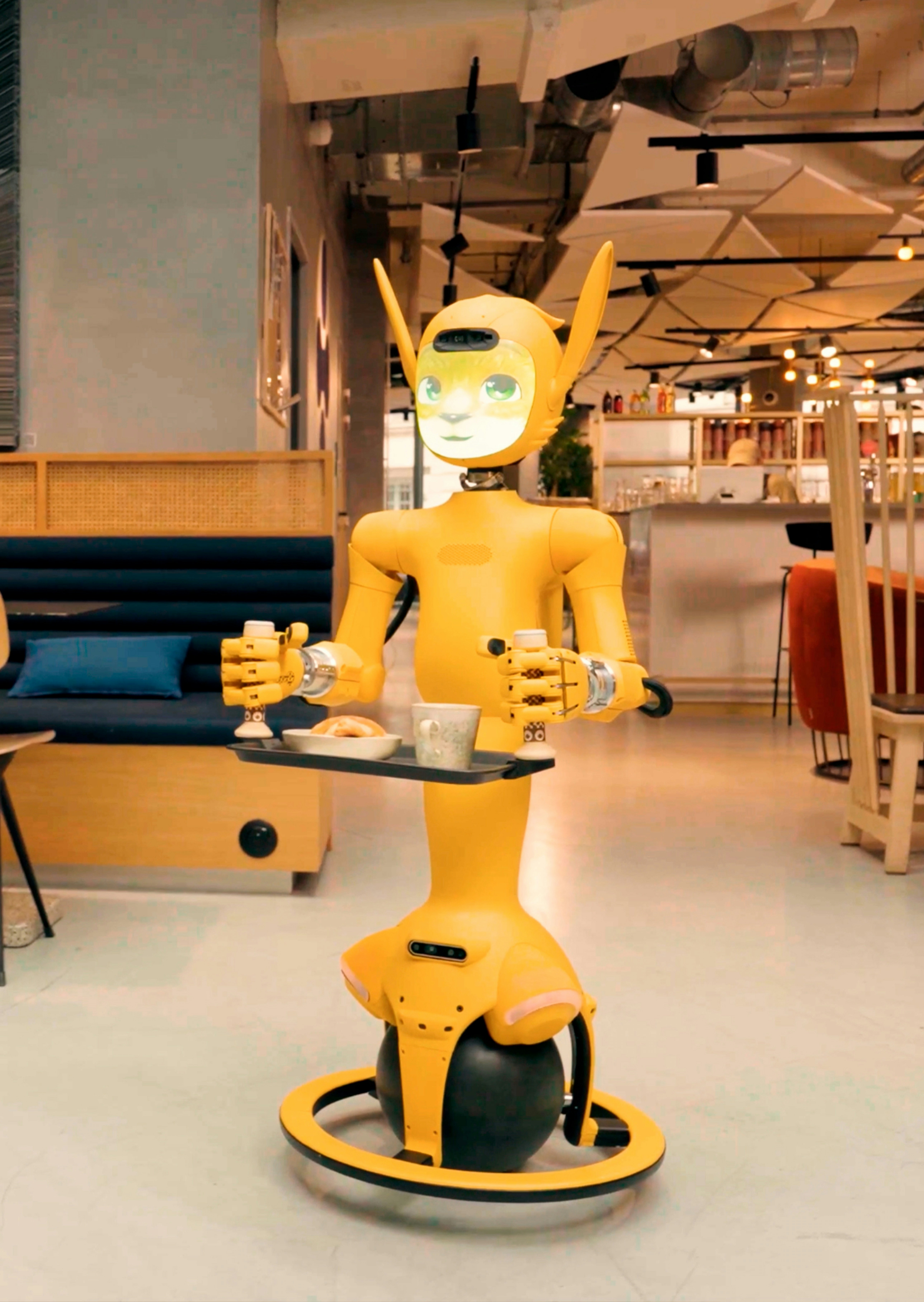 A yellow robot serving drinks and food in a cafe photo – Free ...