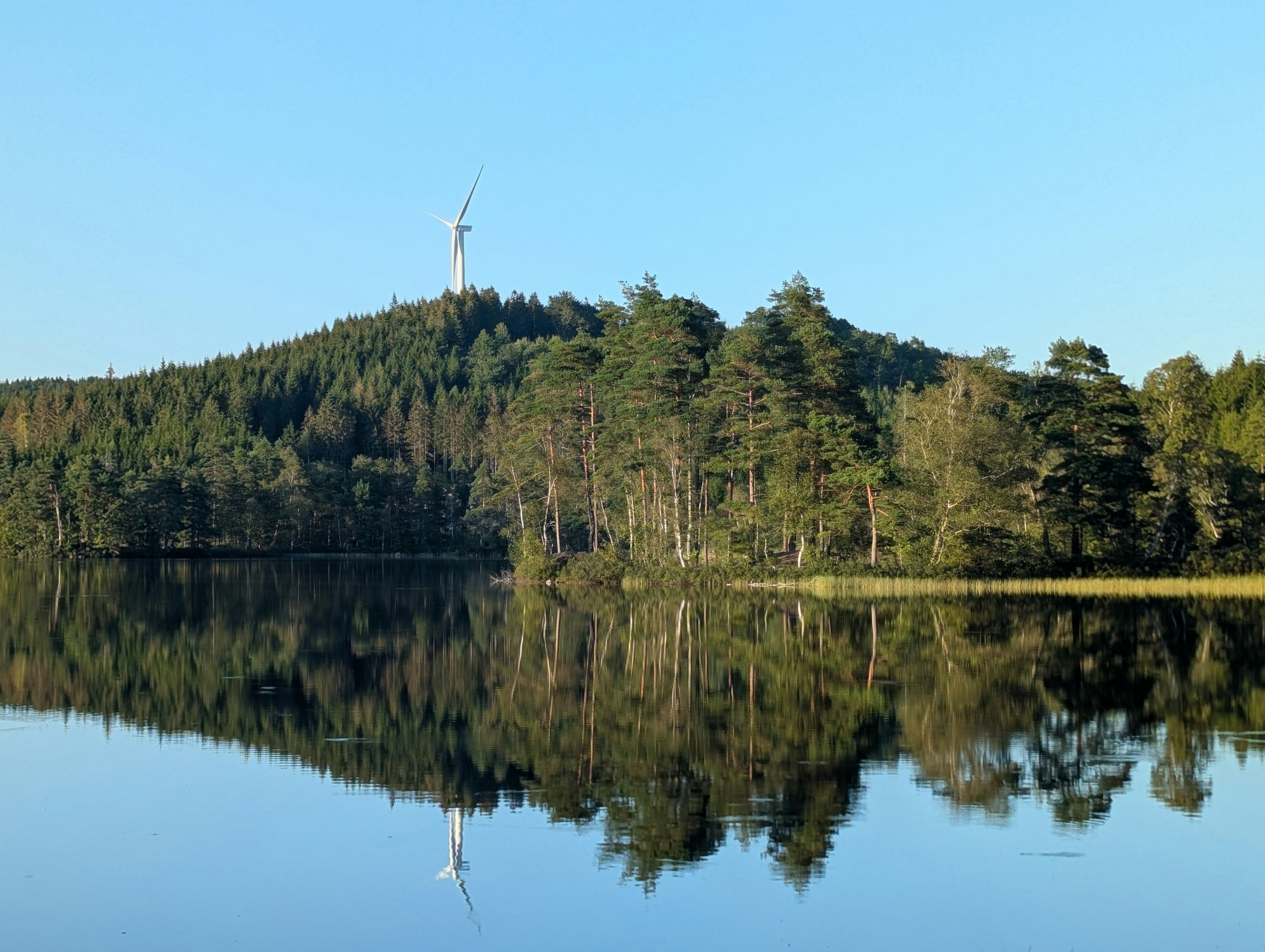 Silent Peak: Wind Turbine Above a Mirror-Lake Forest