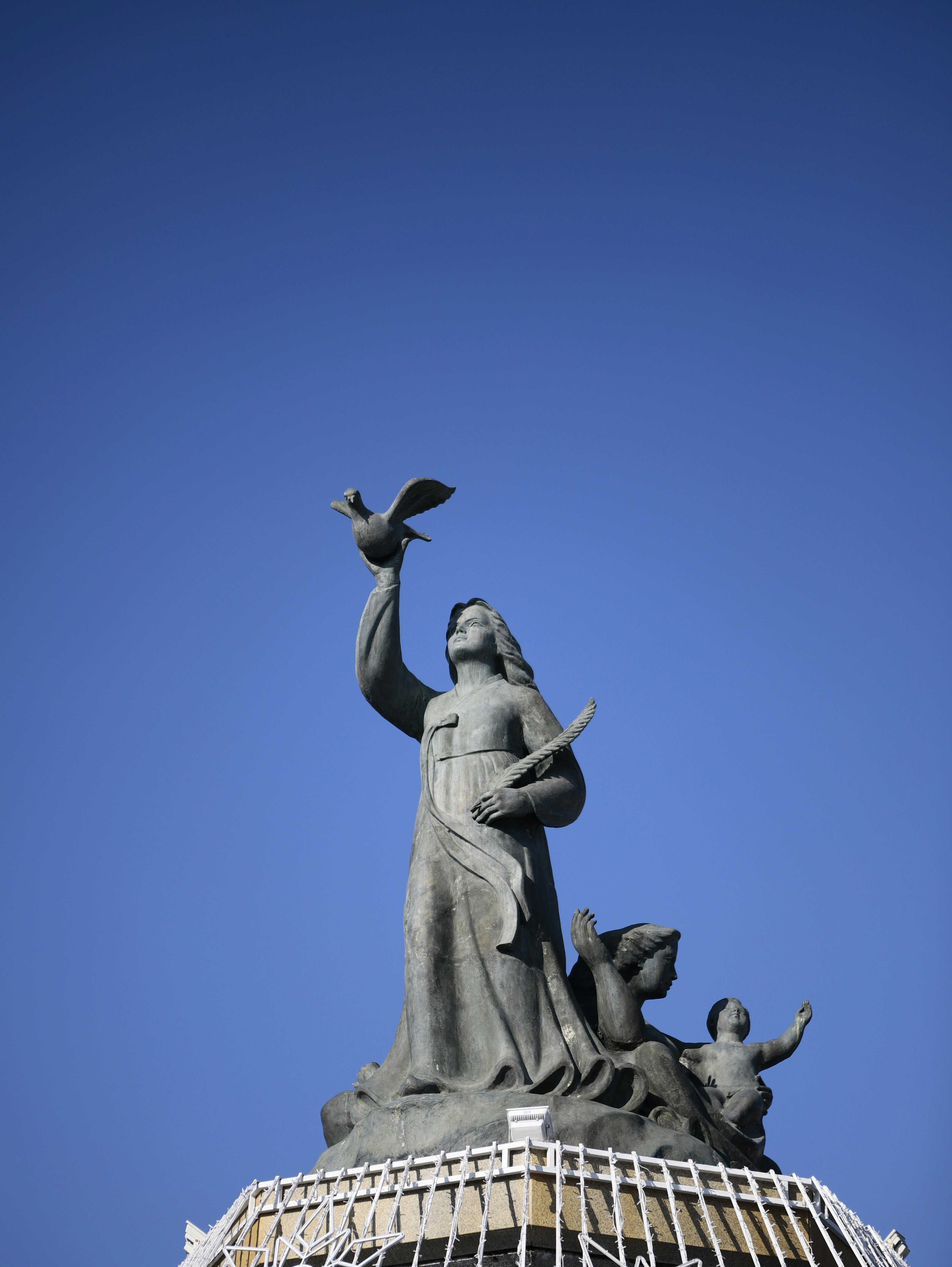 Winged Offer: A Monumental Figure Reaches Toward the Clear Sky