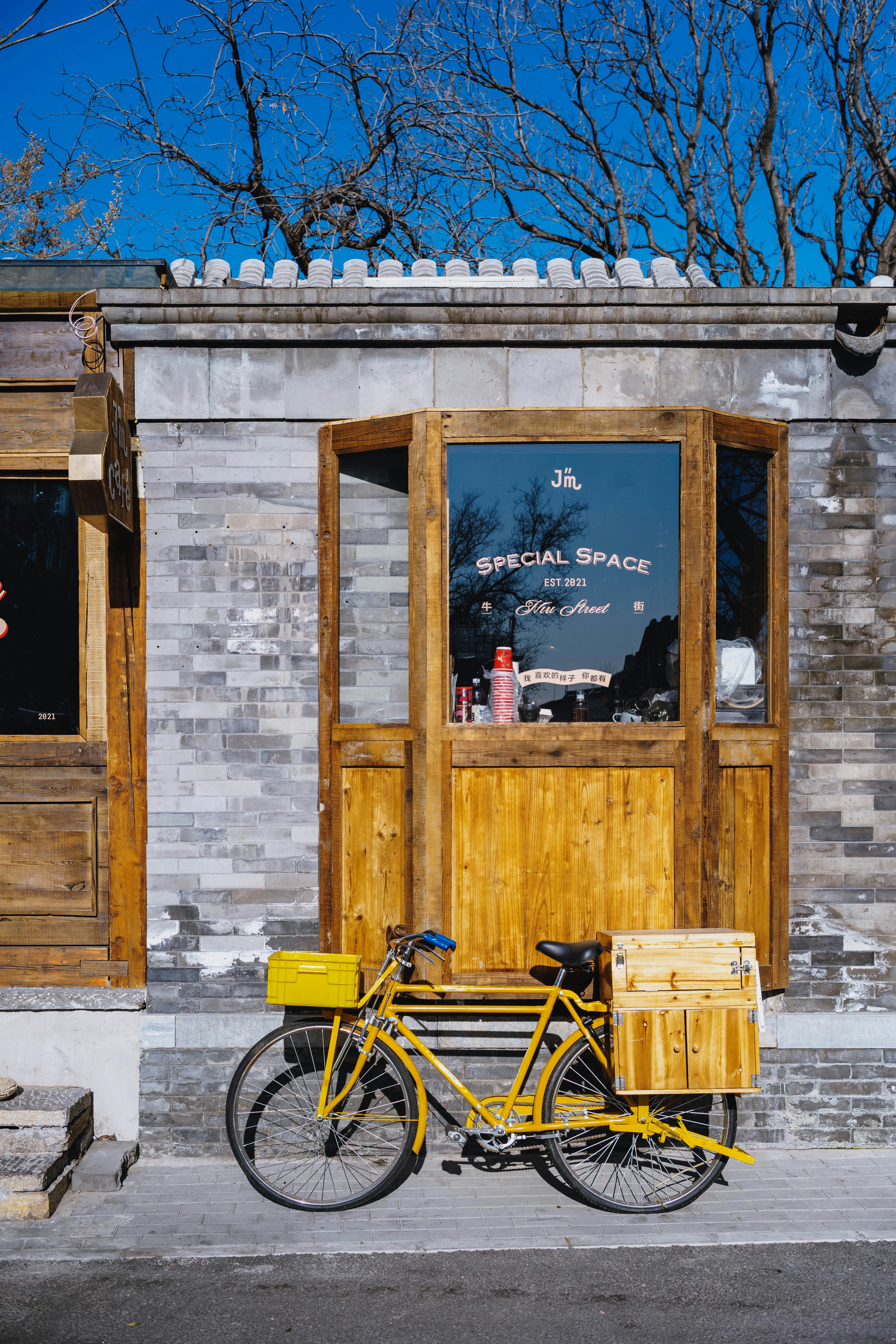 Yellow Cargo Bike in Front of a Rustic Wood-Frame Shop Window