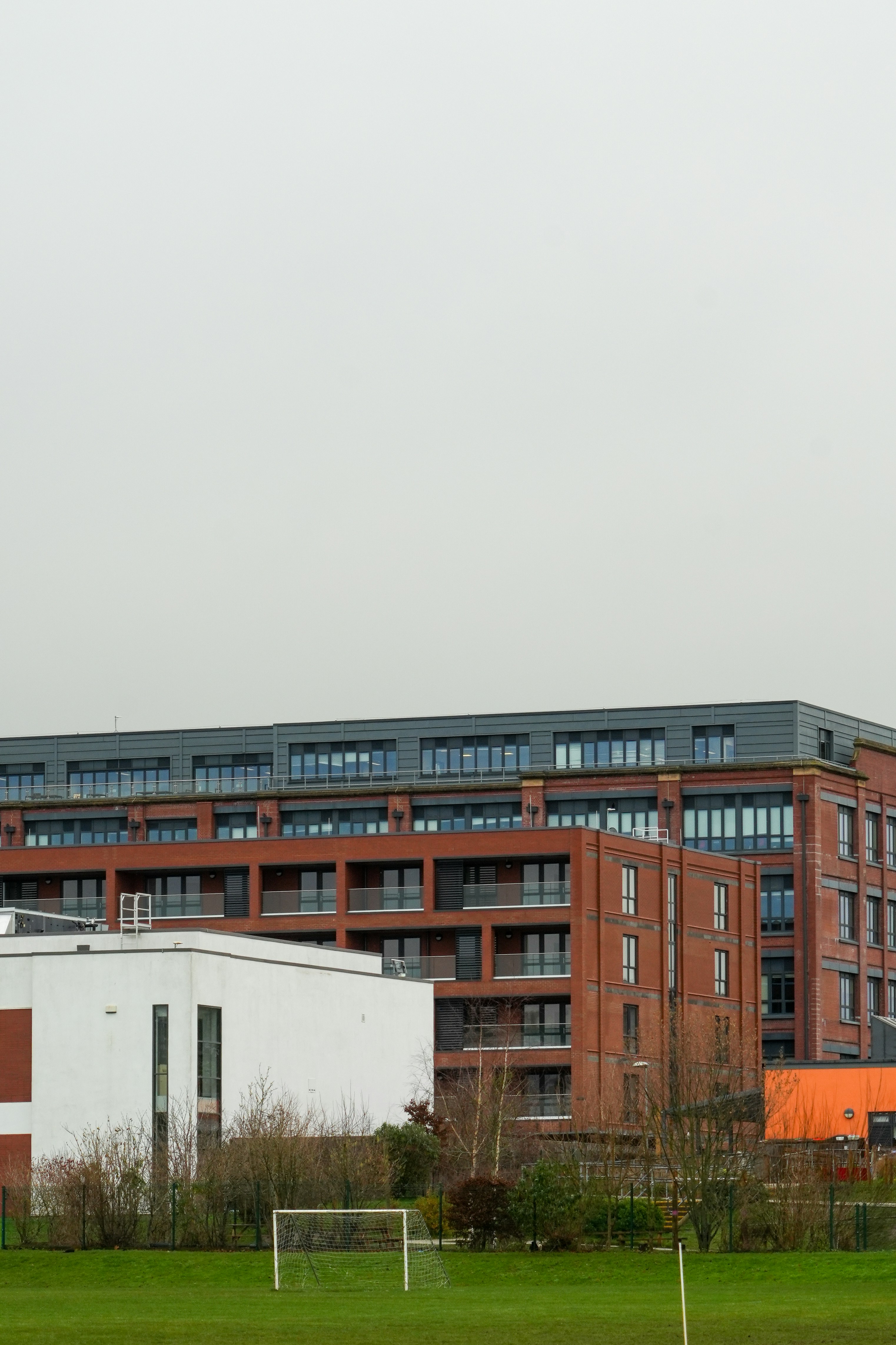 Urban Horizon: Brick Facades and Green Field Press Against a Pale Sky