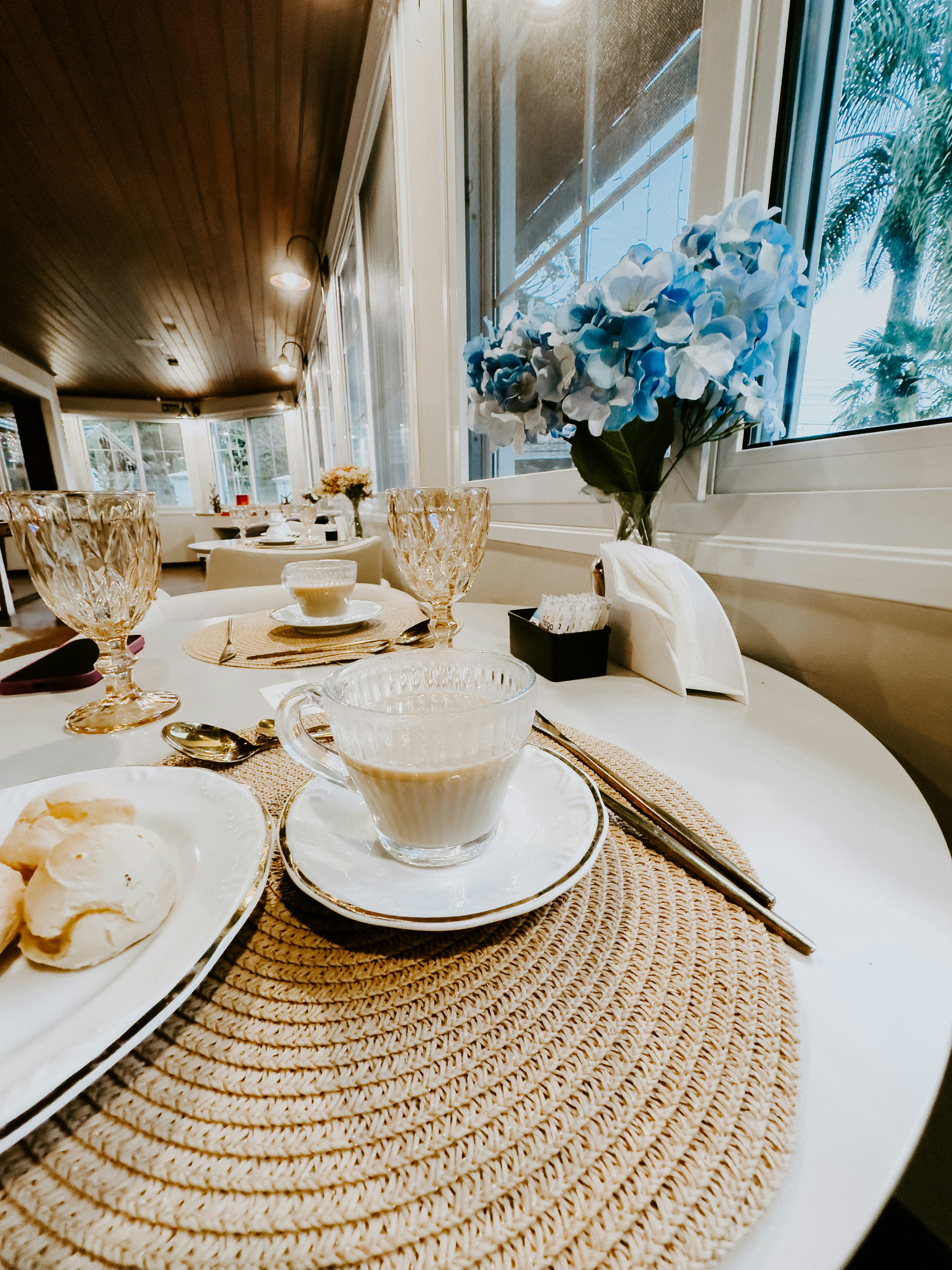 Candlelit Breakfast Setup with Blue Hydrangeas by a Serene Window
