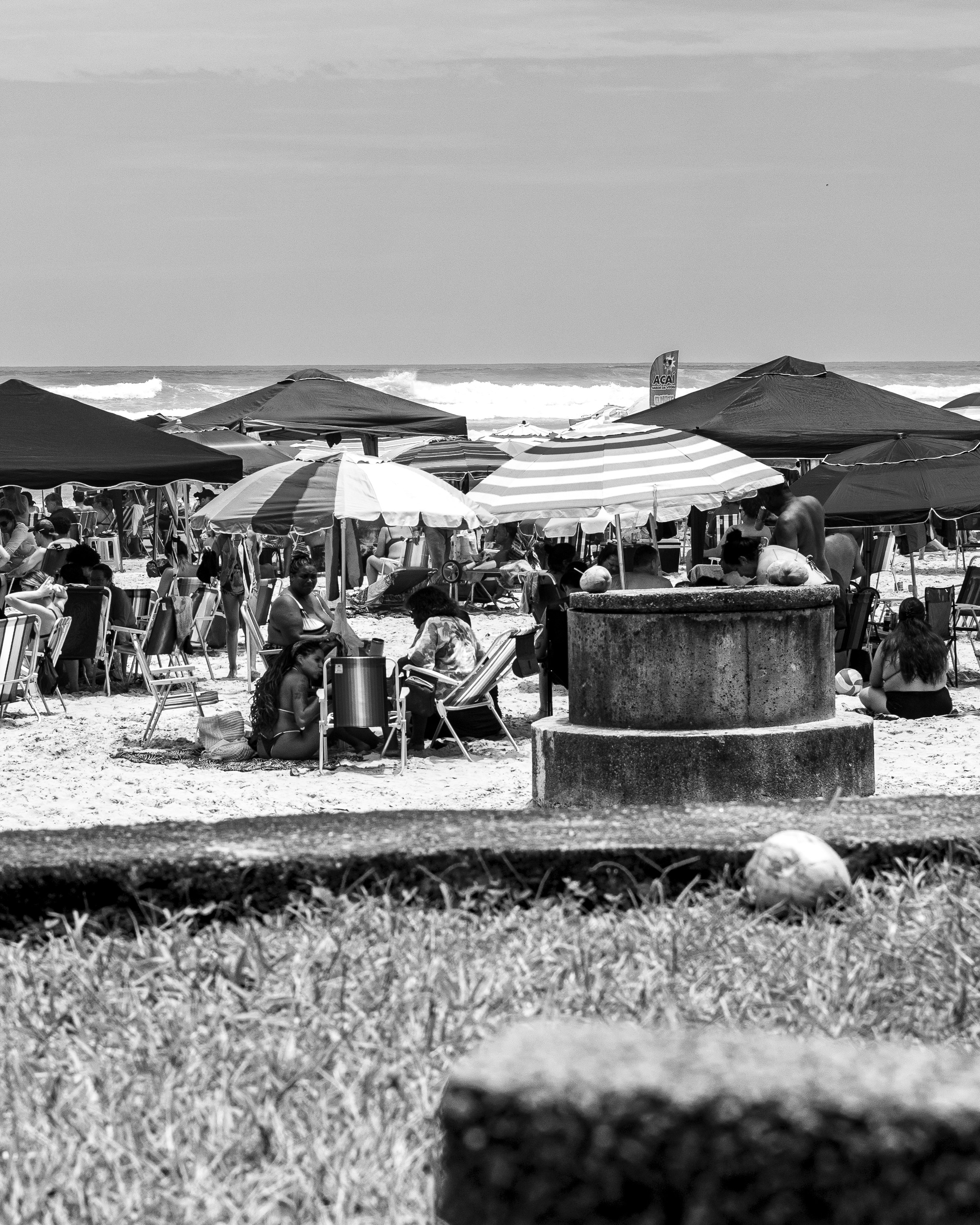 Sunlit Beach Club: People, Parasols, and a Weathered Well