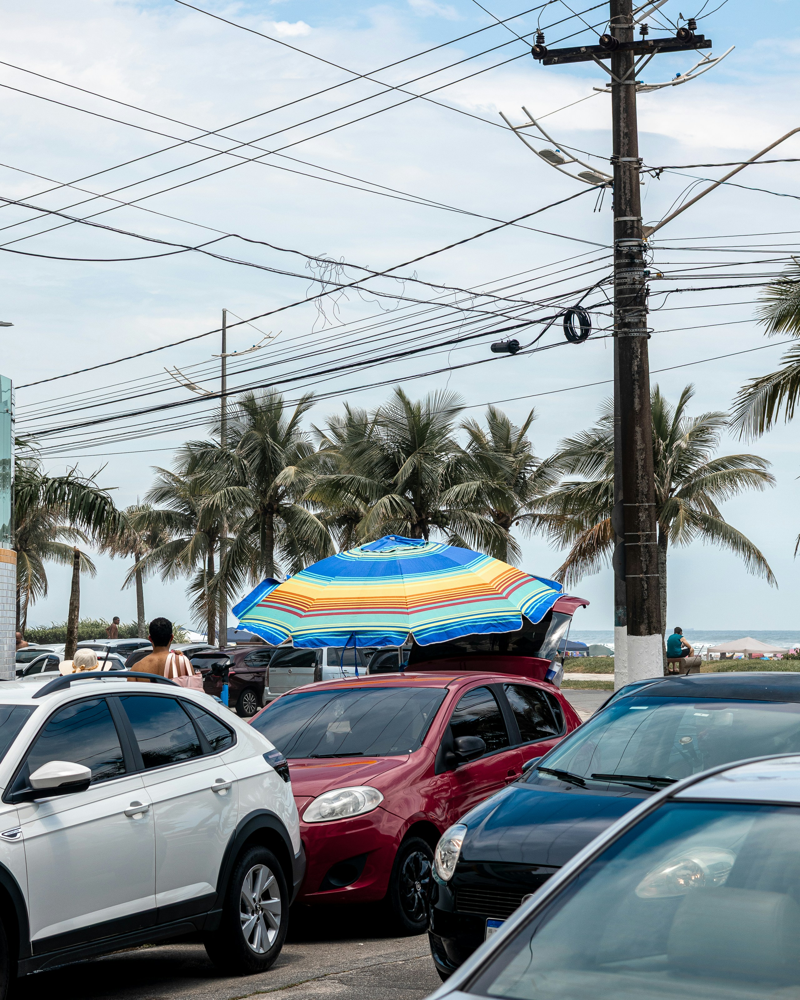 Sunlit Beachside Parking Scene Under a Rainbow Umbrella