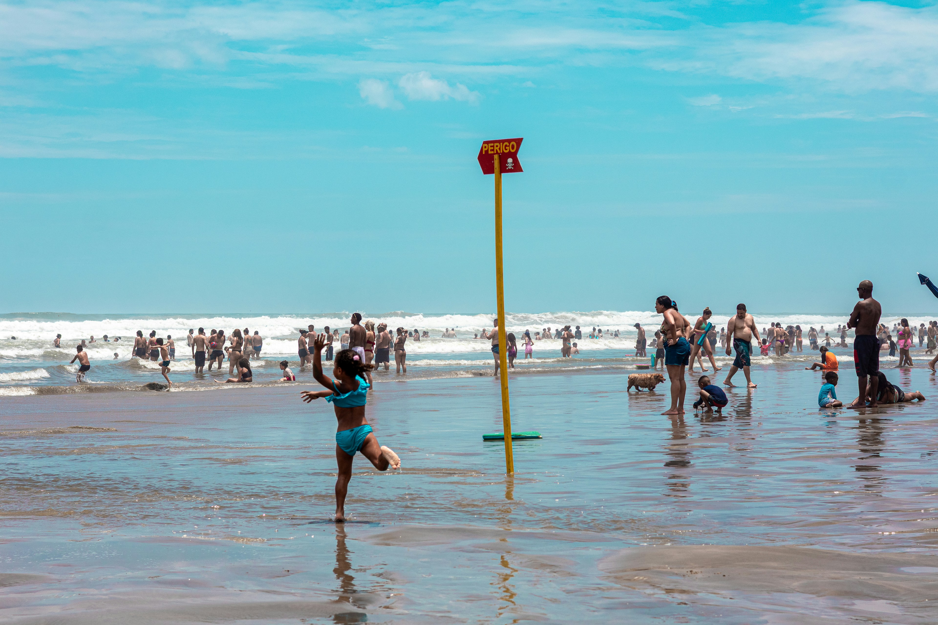 Sunlit Beach Shuffle: A Playful Jump Near a Signpost