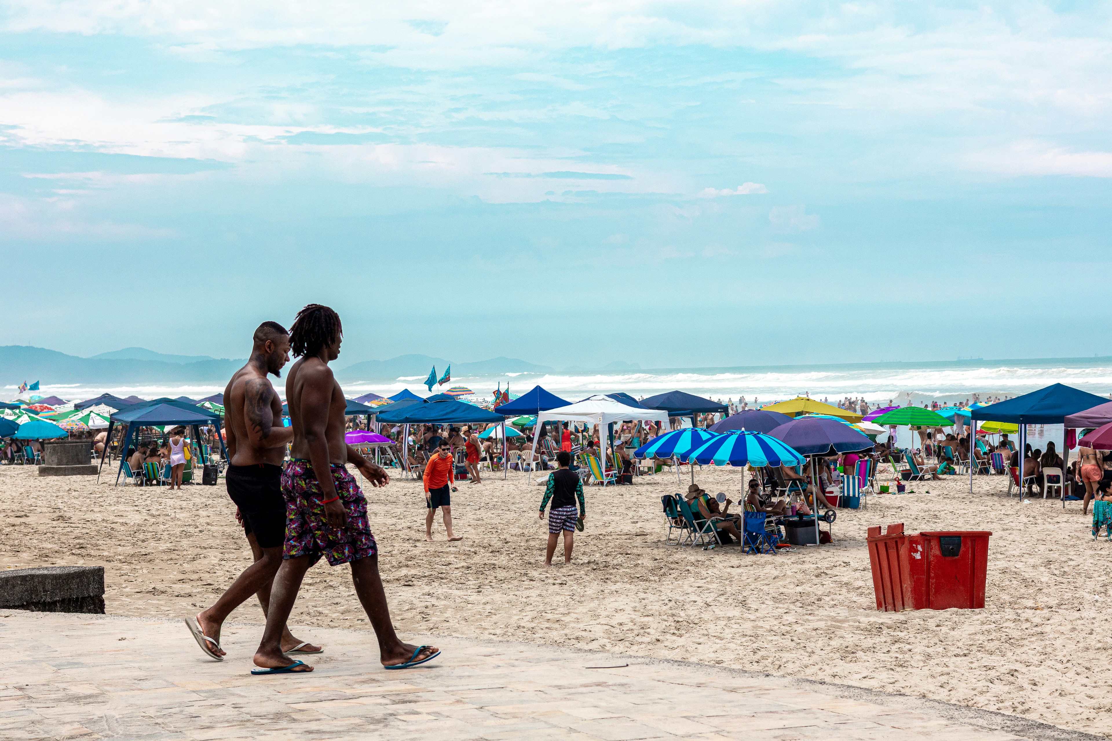 Beach Stroll: Two young men walking along a crowded shore