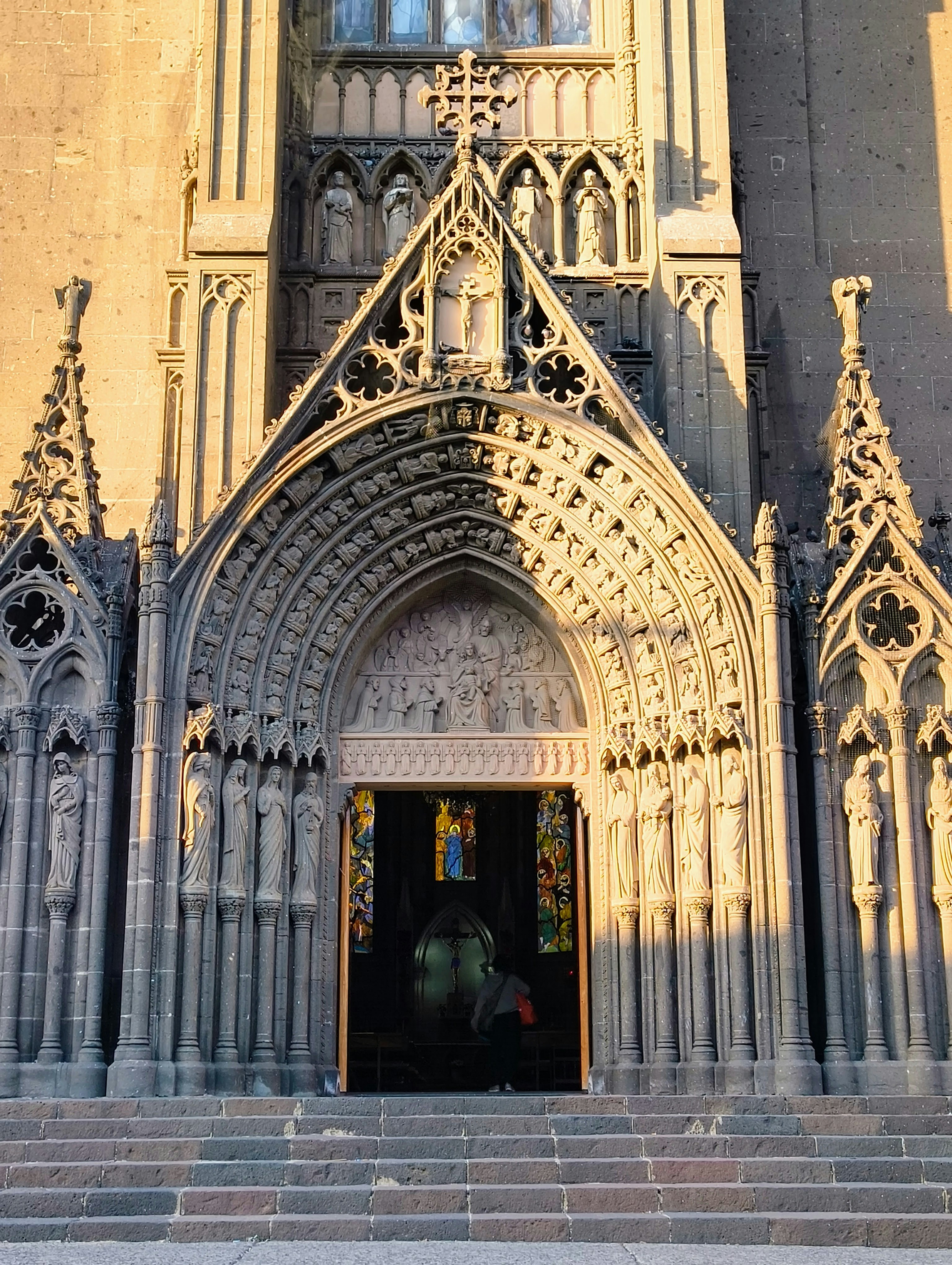 Dintel principal Fachada de la Parroquia Nuestra Señora del Rosario, también conocido como Templo del Padre Galván, en la colonia El Retiro de Guadalajara, México. El edificio de estilo neogótico, fue construido por el arquitecto Pedro Castellanos Lambley, y luego de su muerte (26 de septiembre de 1961), el ingeniero civil Ricardo Agraz Sainz continuó la edificación. Todas las figuras, arcos, estatuas, volutas, flores, caireles, fueron realizados por el escultor tallista José Refugio Godínez, durante más de medio siglo.