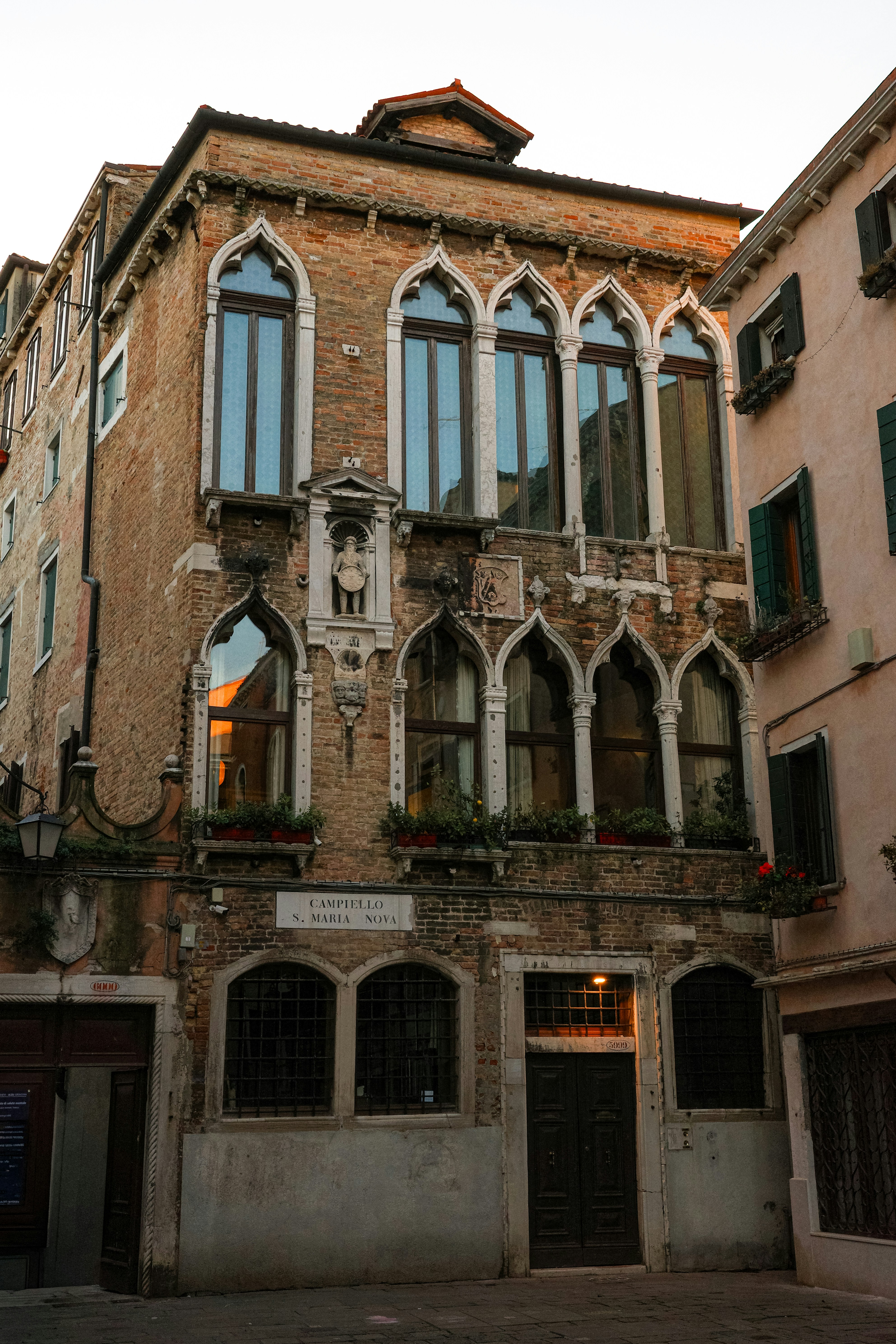 Venetian Gothic Facade: Arched Windows and Brickwork in the Narrow Street