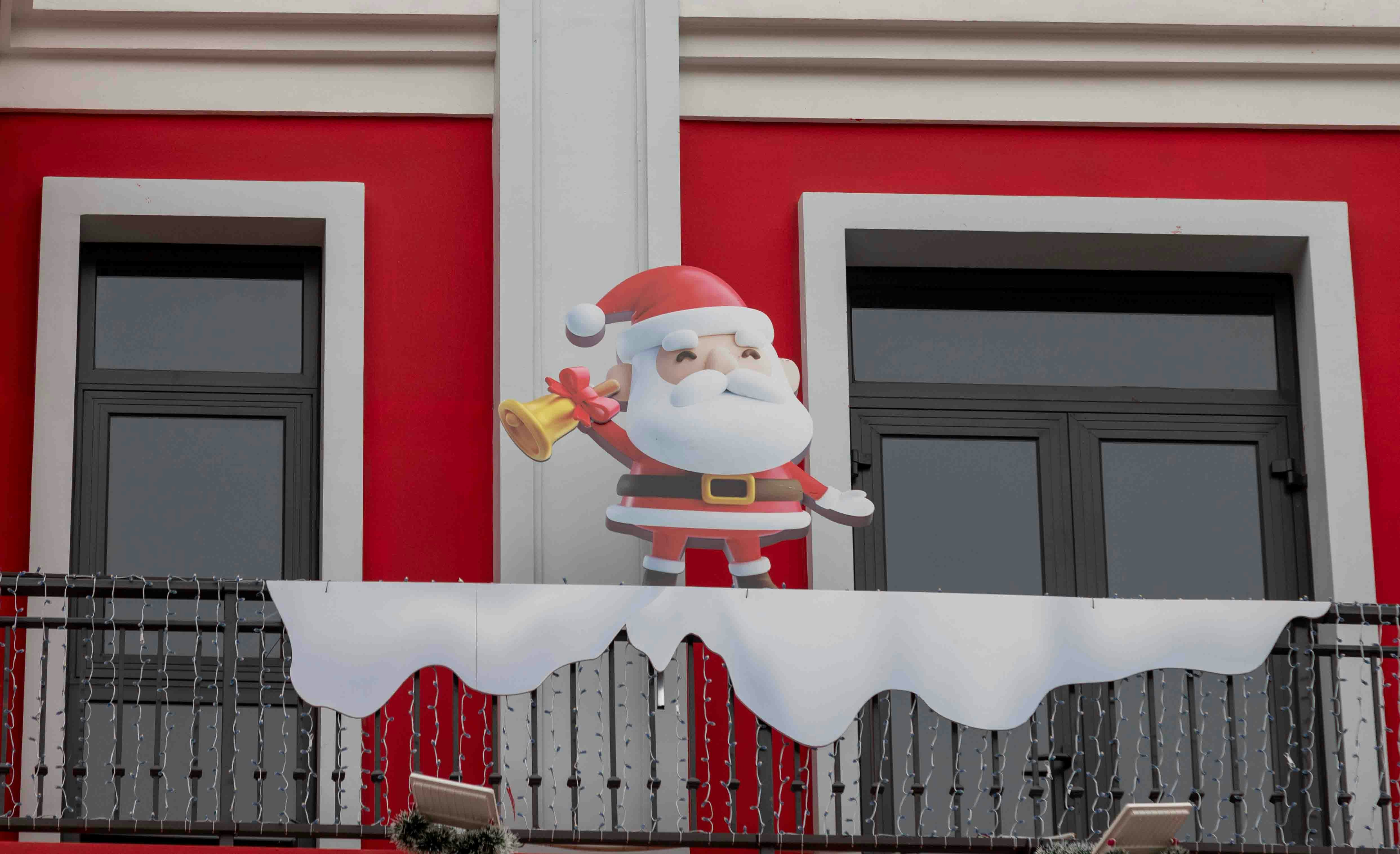 Santa on the Balcony: Festive Facade Over Red Walls