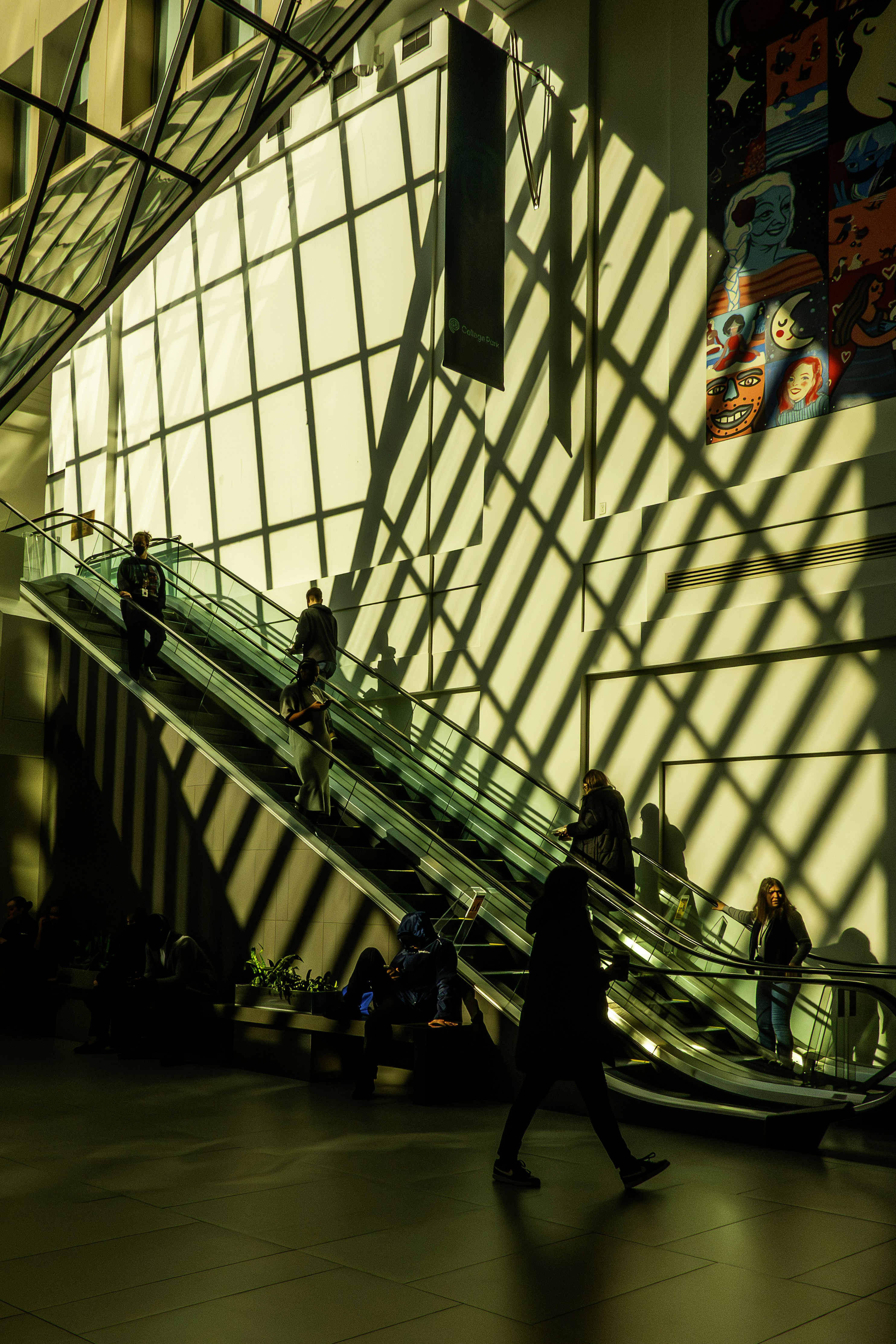 Shadowed Geometry: People on an Escalator Beneath Sunlit Stripes