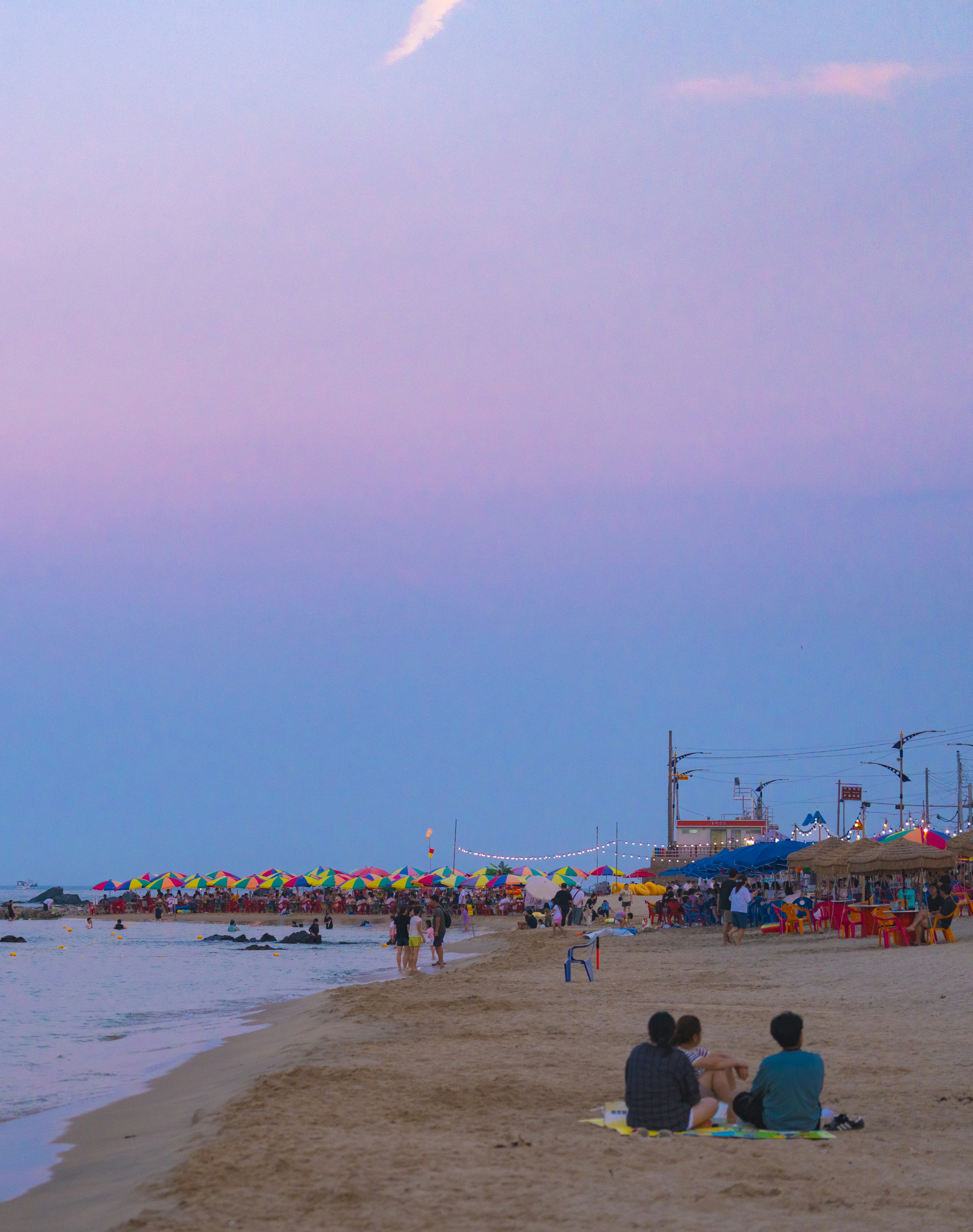 Sunset on the Busy Beach: A Quiet Moment Among Colorful Umbrellas