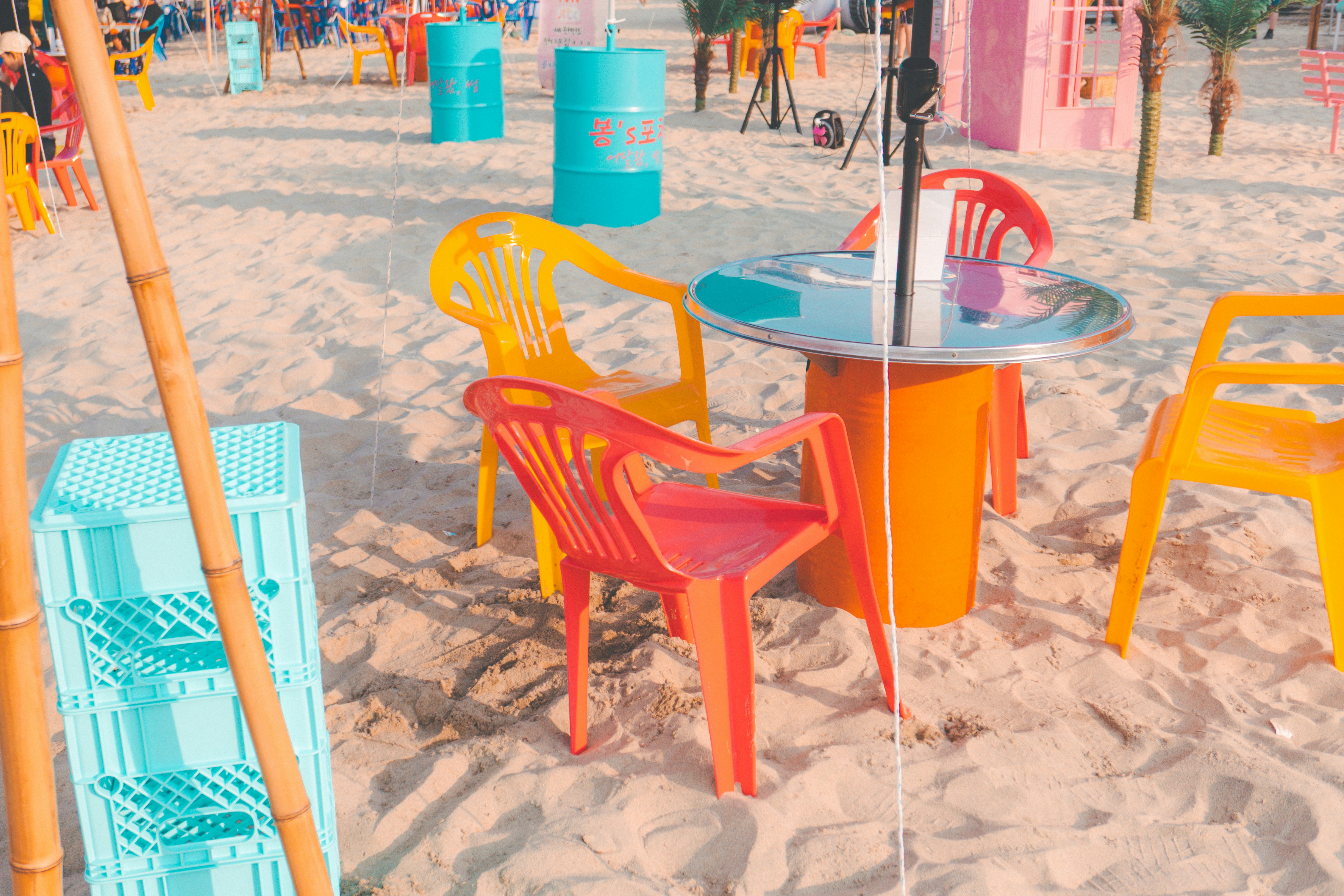 Colorful chairs and table on a sandy beach.