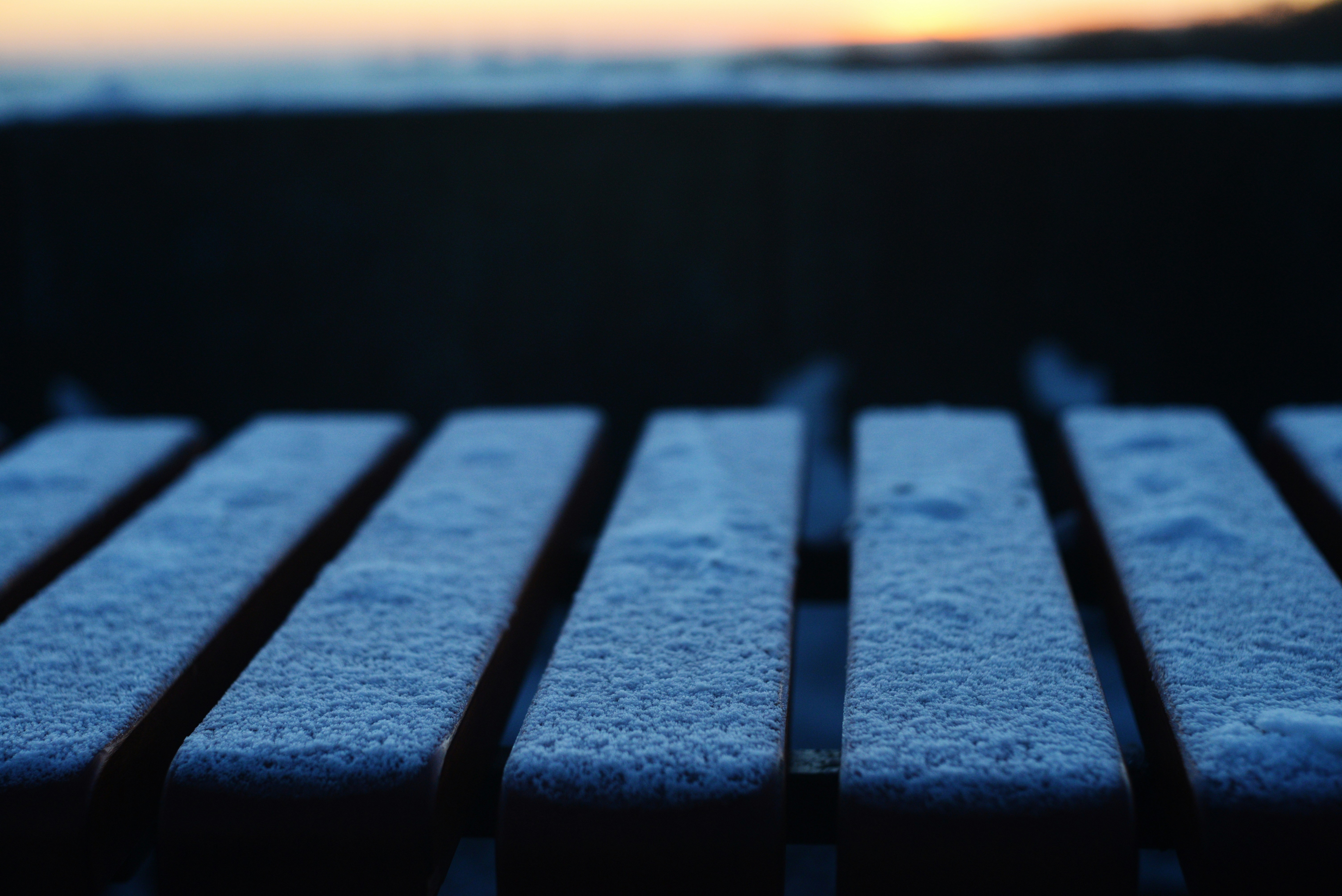 Frosted Park Benches: Evening Light on Snow-Capped Slats