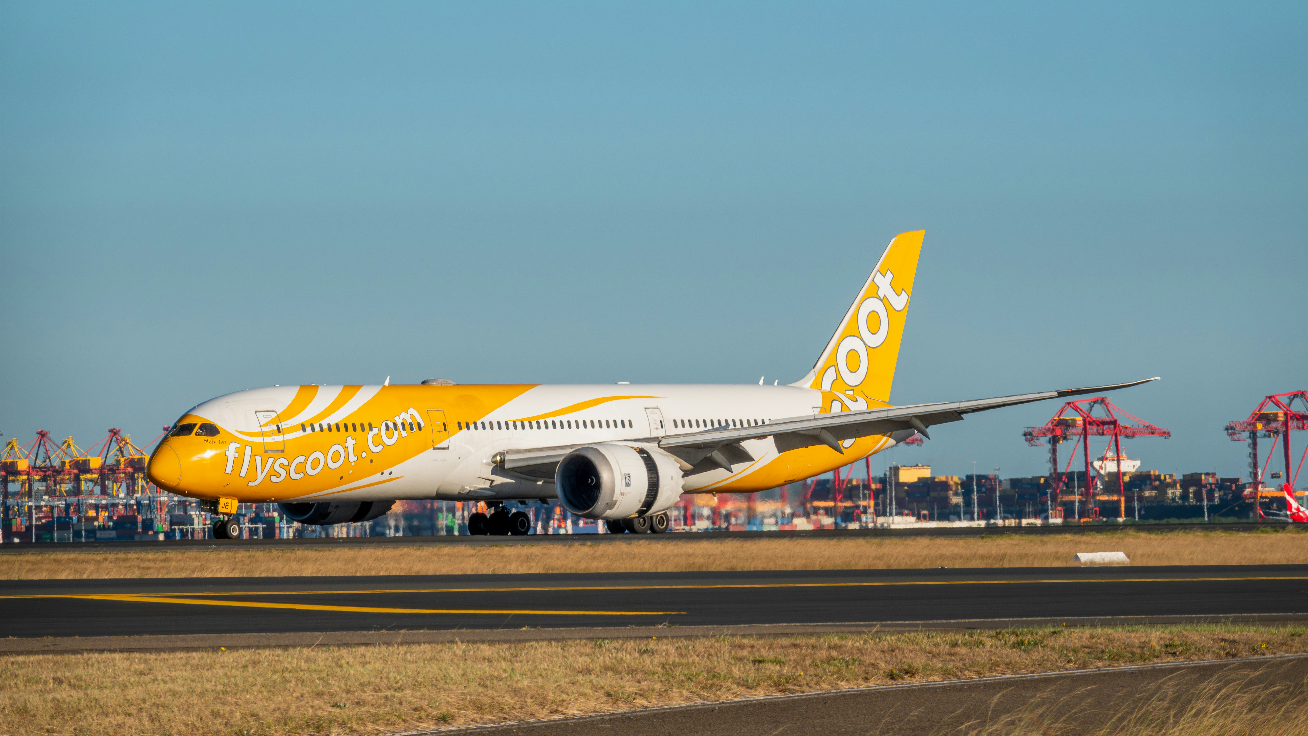 Brightly Painted Flyscoot: A yellow-tiled jet at the runway edge