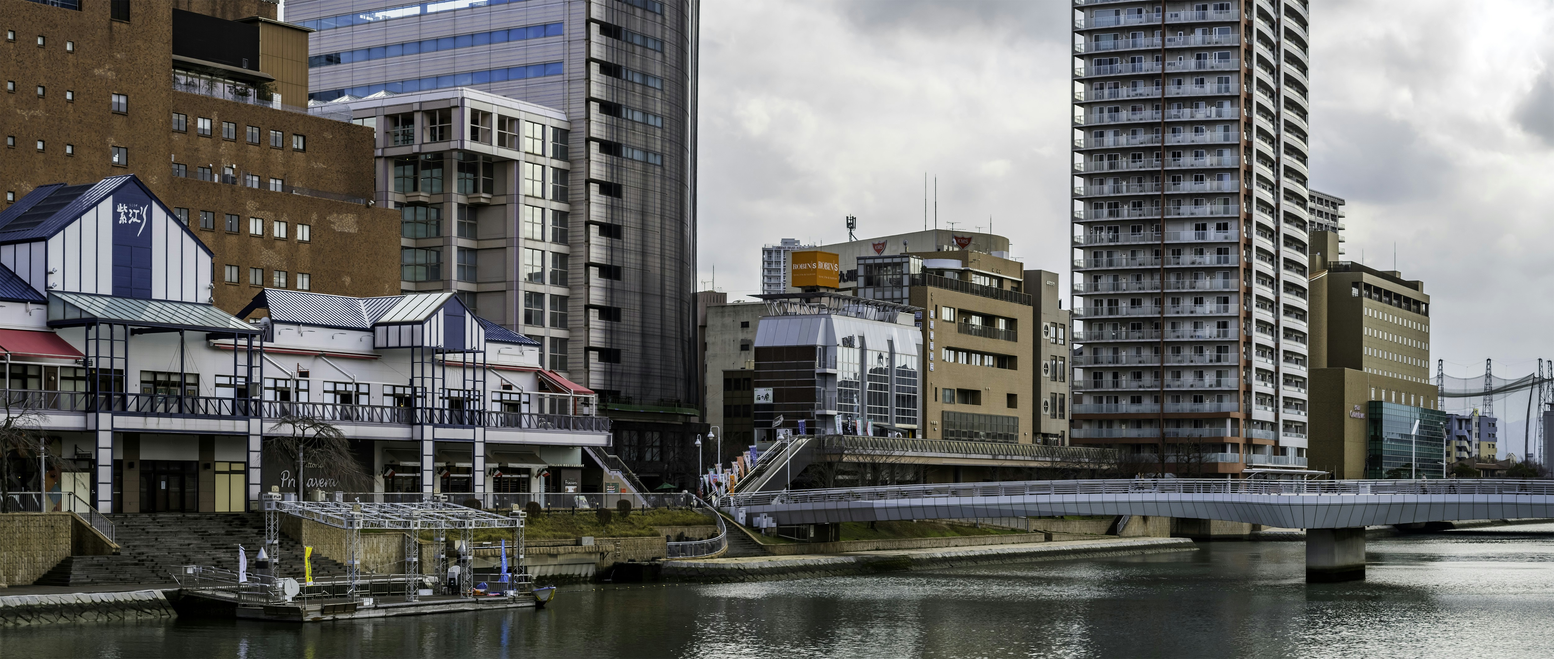 Modern cityscape with buildings and a bridge over water.