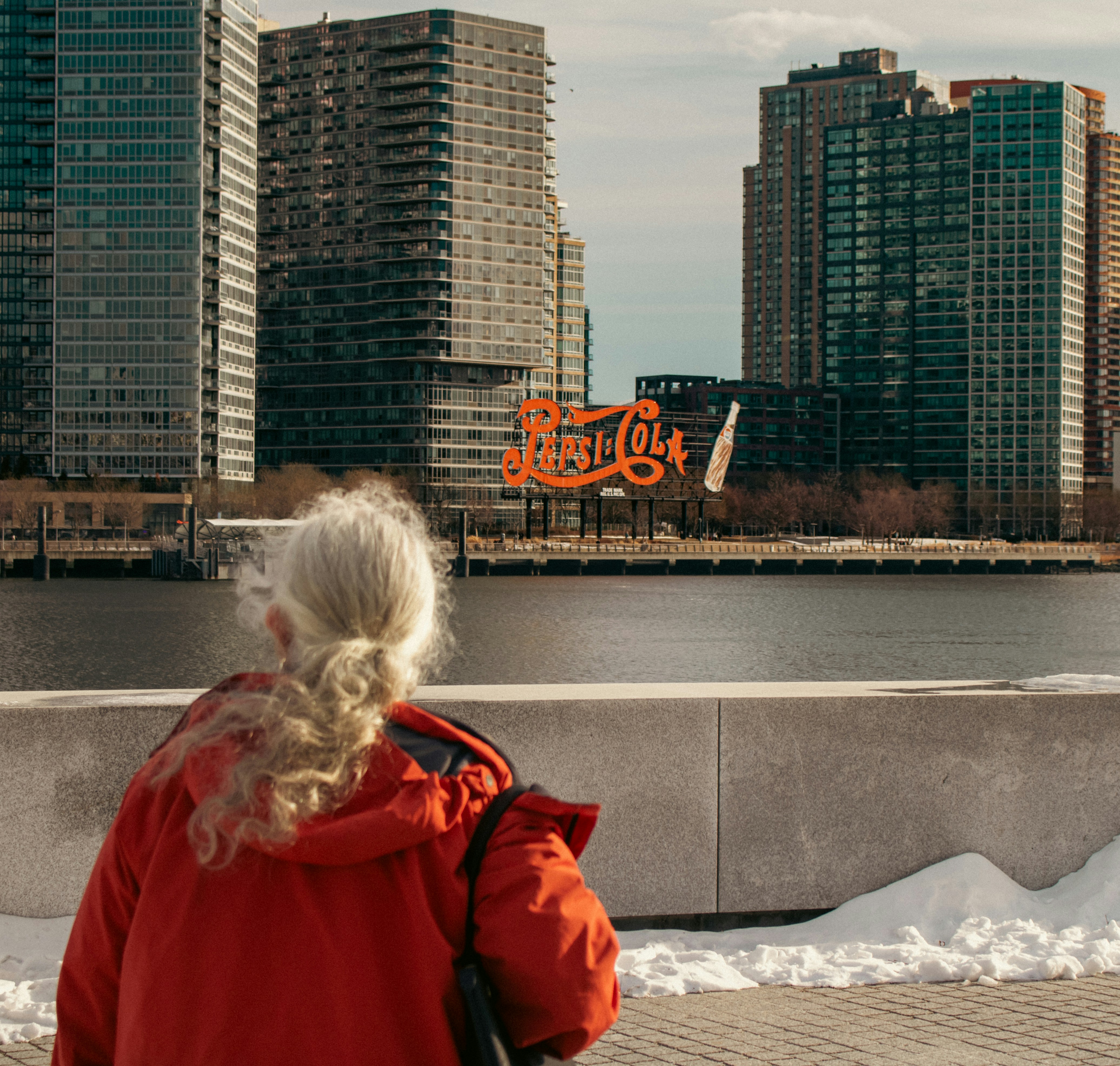 Red Coat, Riverfront Vista: Viewer Lingers on the Stranger by the Water