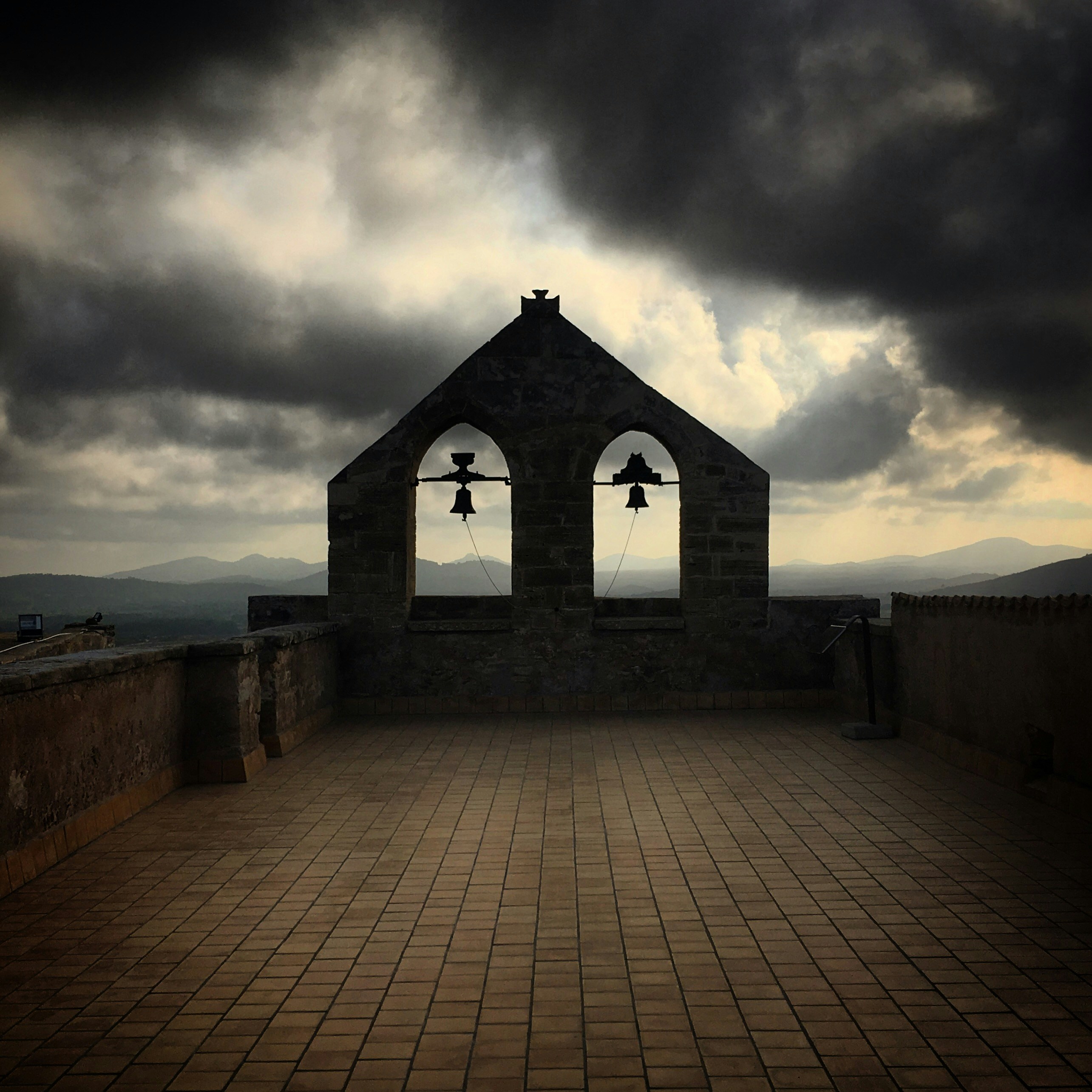 Silhouetted Bell Archframe Against Stormy Horizon