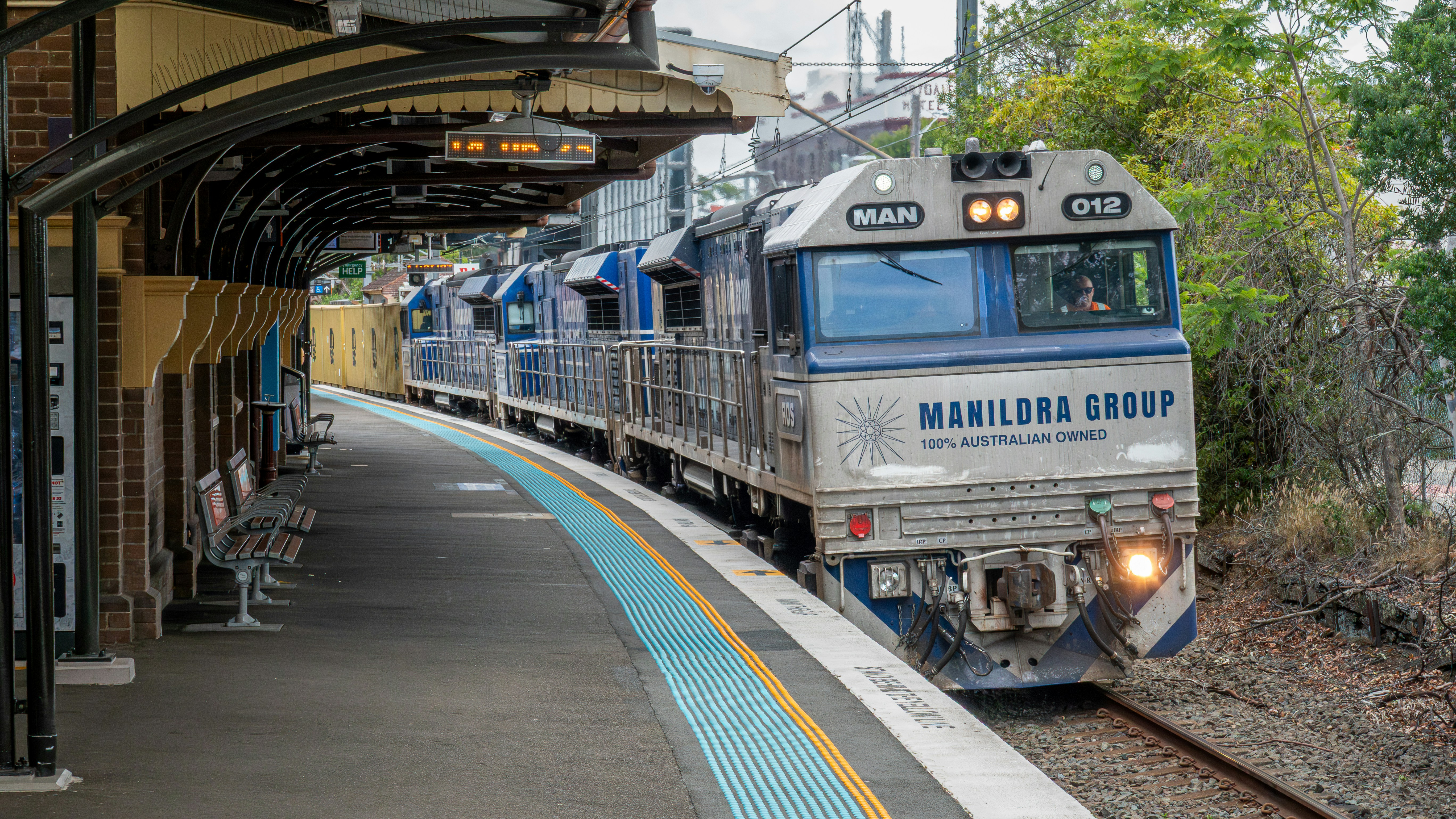 Platform Pulse: A freight train rounds the corner at a quiet suburban station