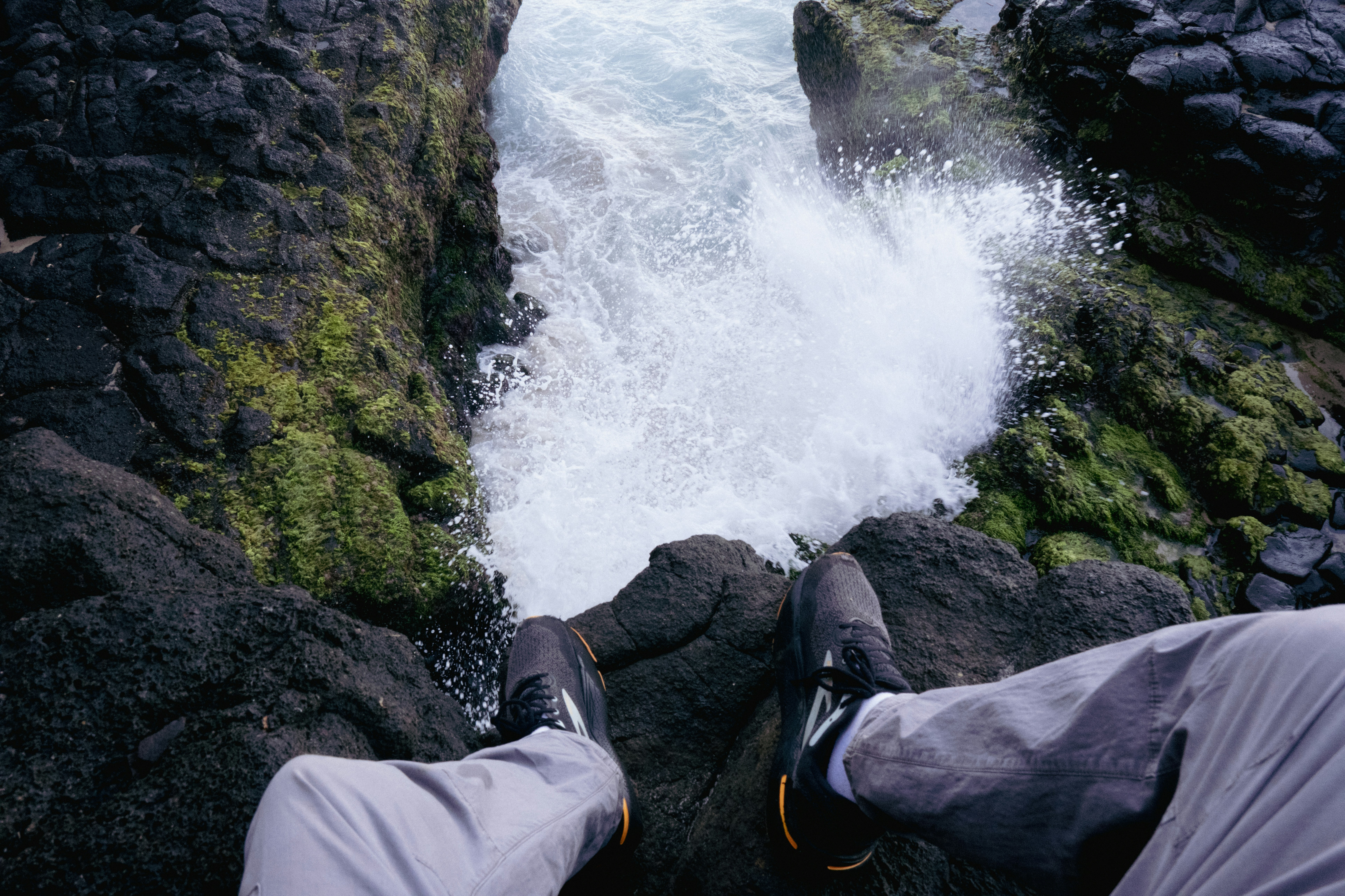Over the Edge: Feet Fixed Over Mossy Black Rocks