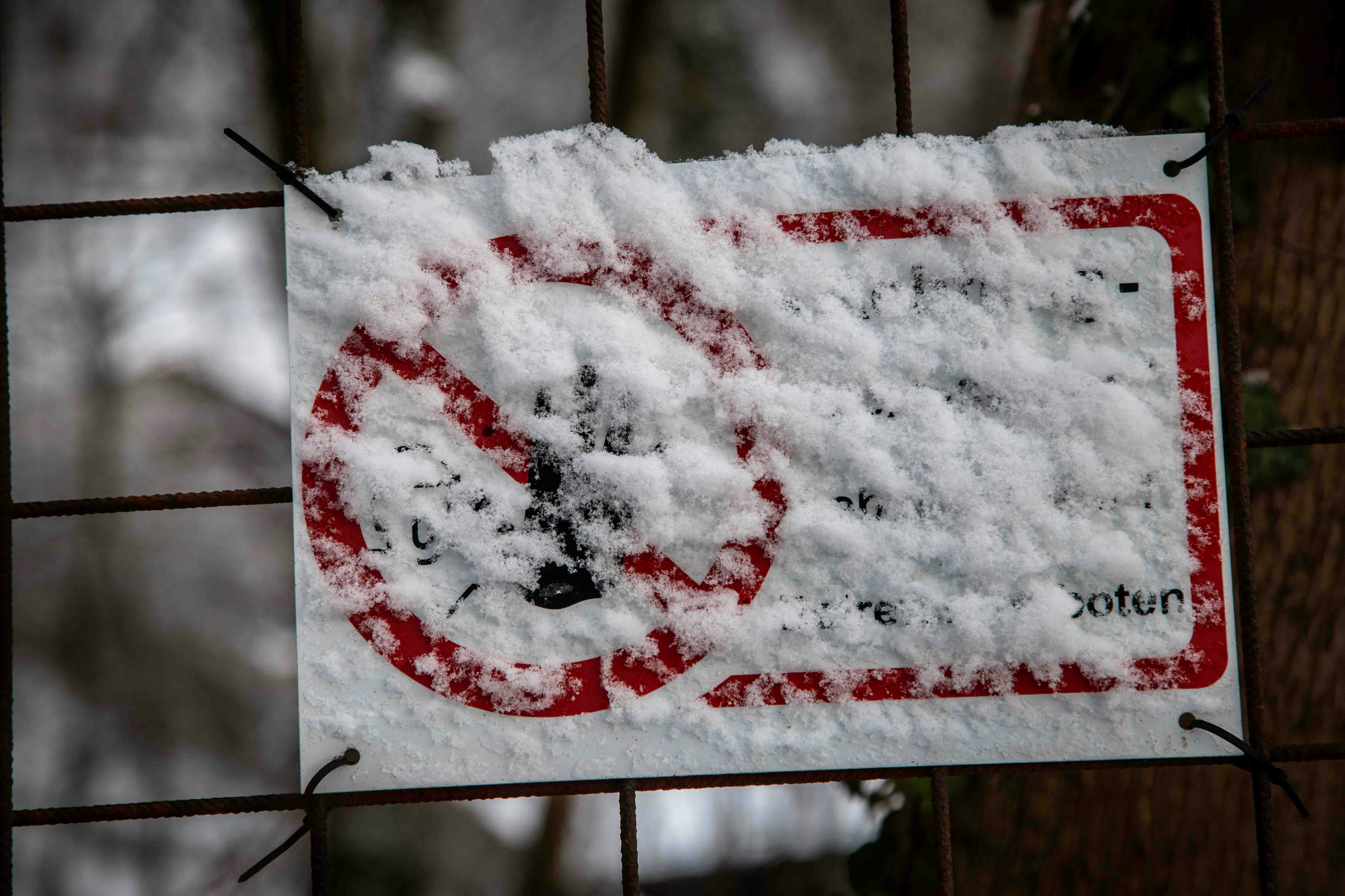 Snow-veiled Warning Sign on Rustic Fence
