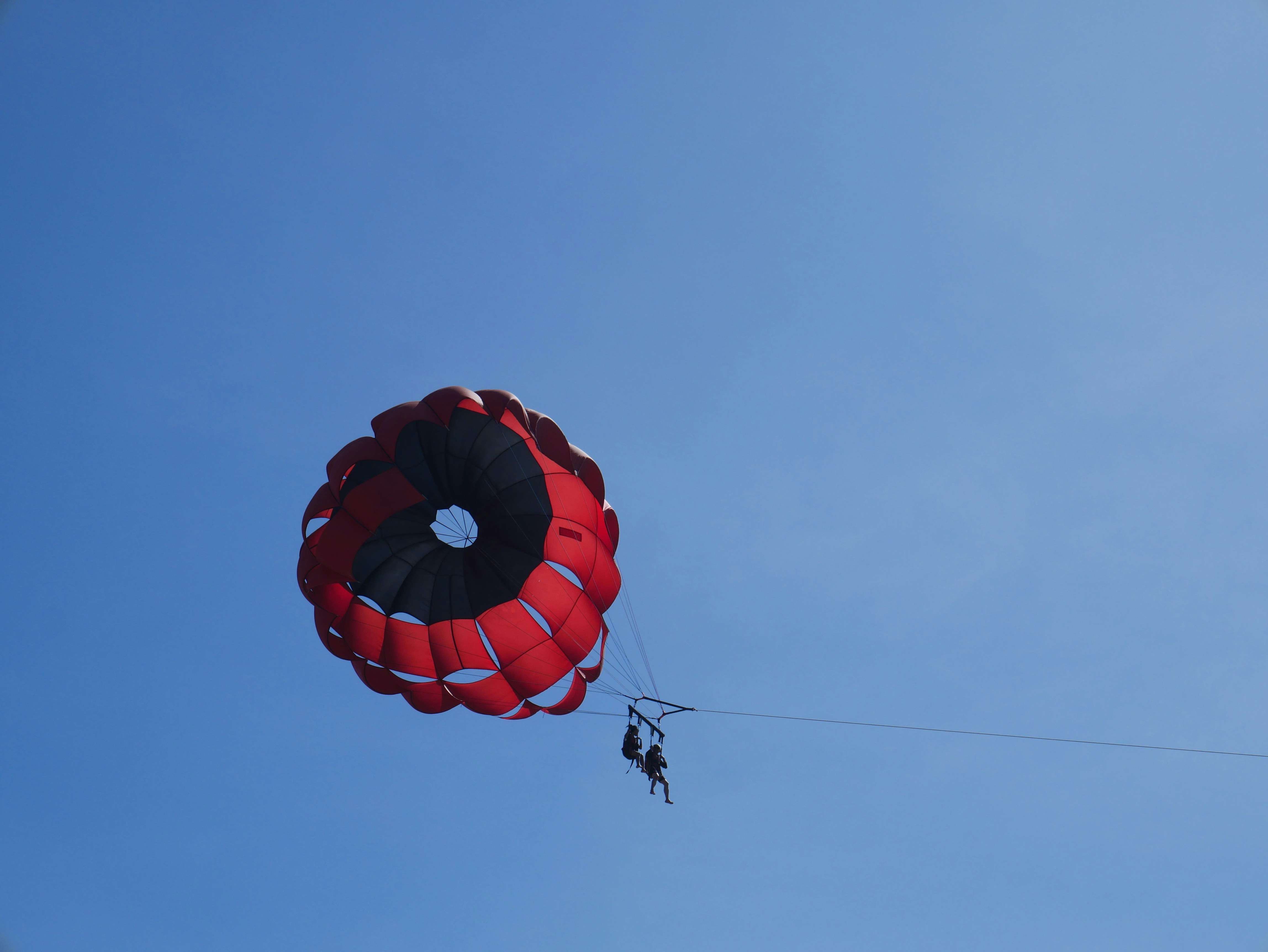 Red Parasail Disc Soaring Against a Clear Blue Sky