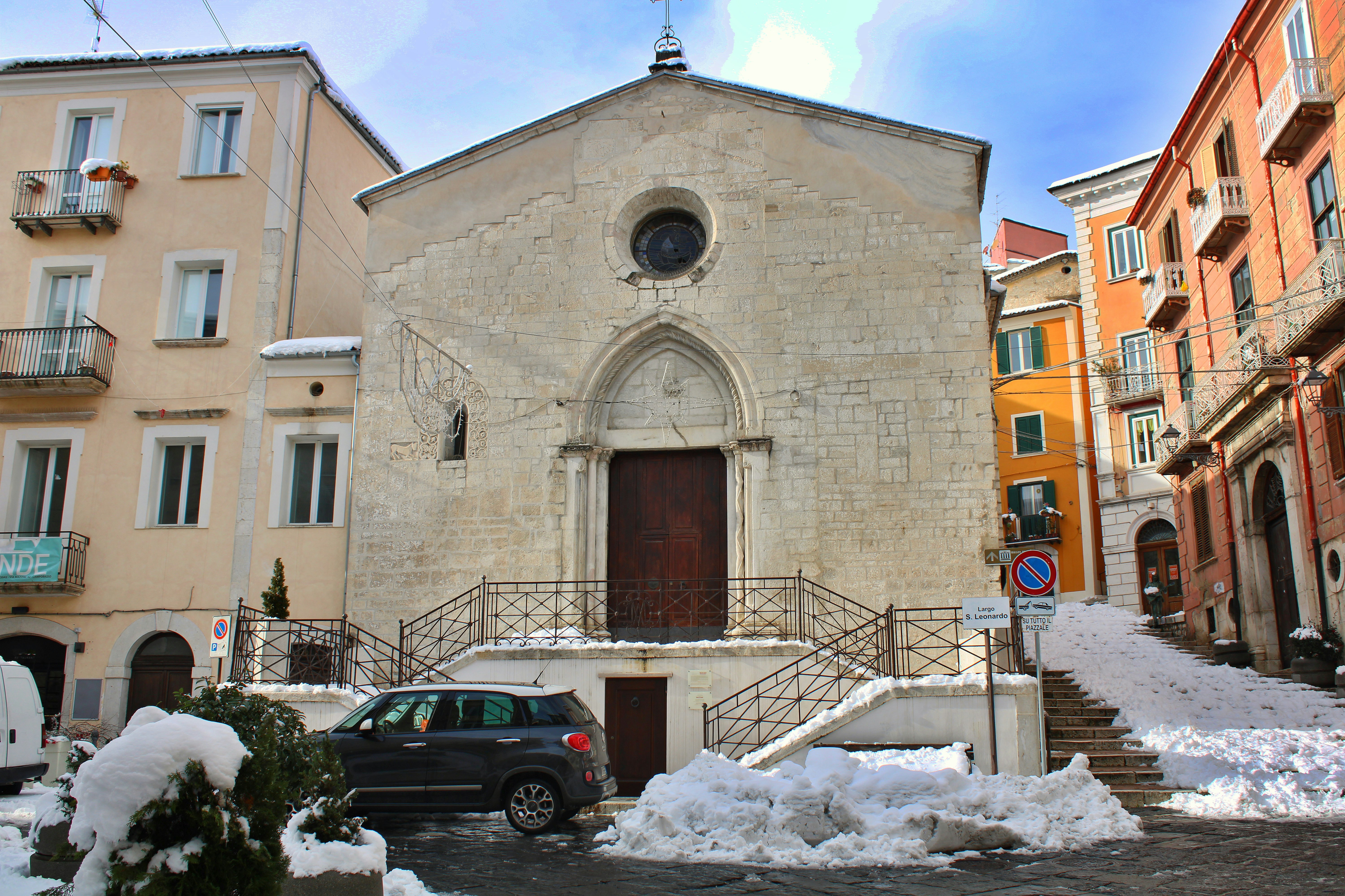 Stone church crowned by a weathered facade in a sunlit alpine street