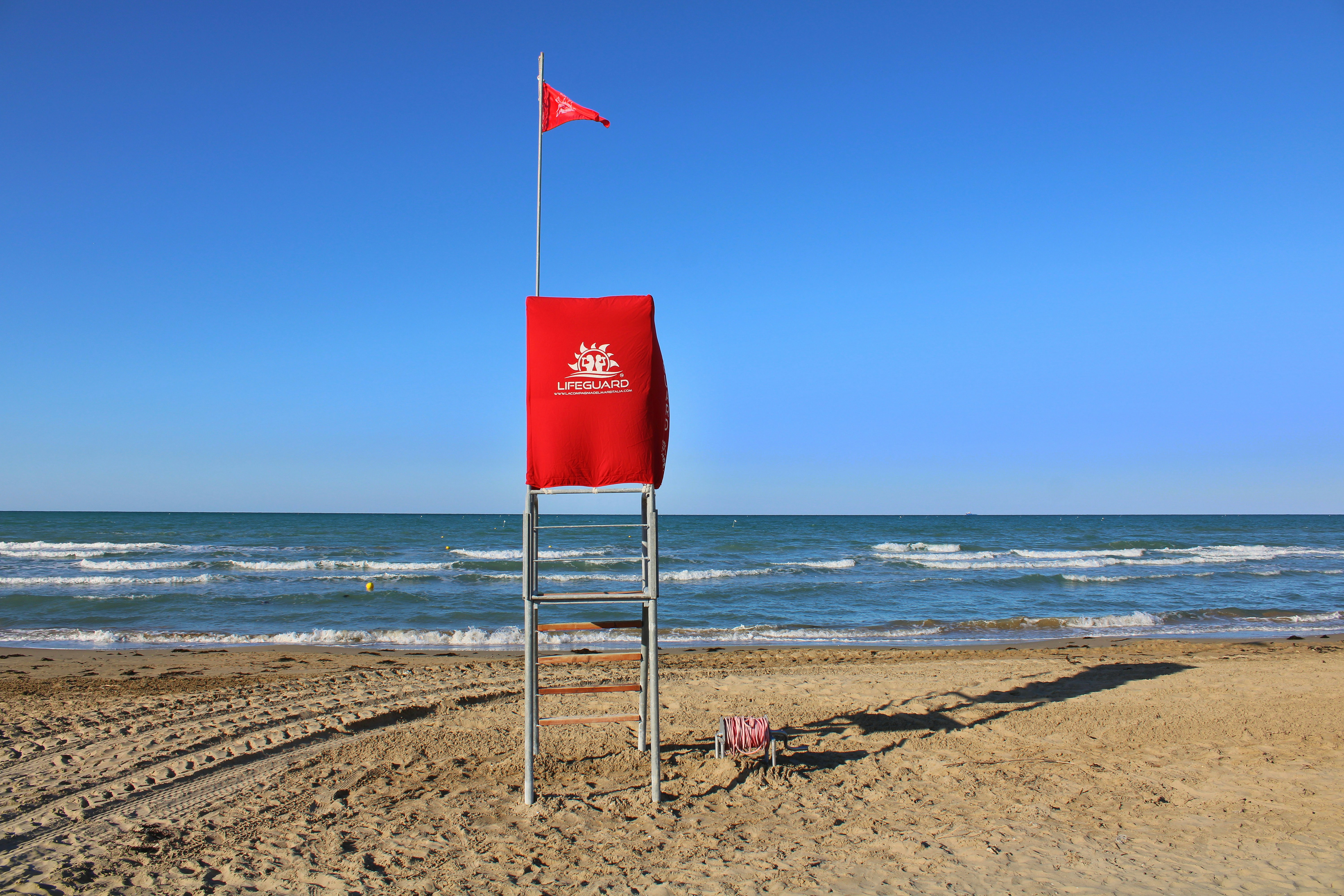 Lifeguard Alert: Crimson Shelter Against a Quiet Blue Sea