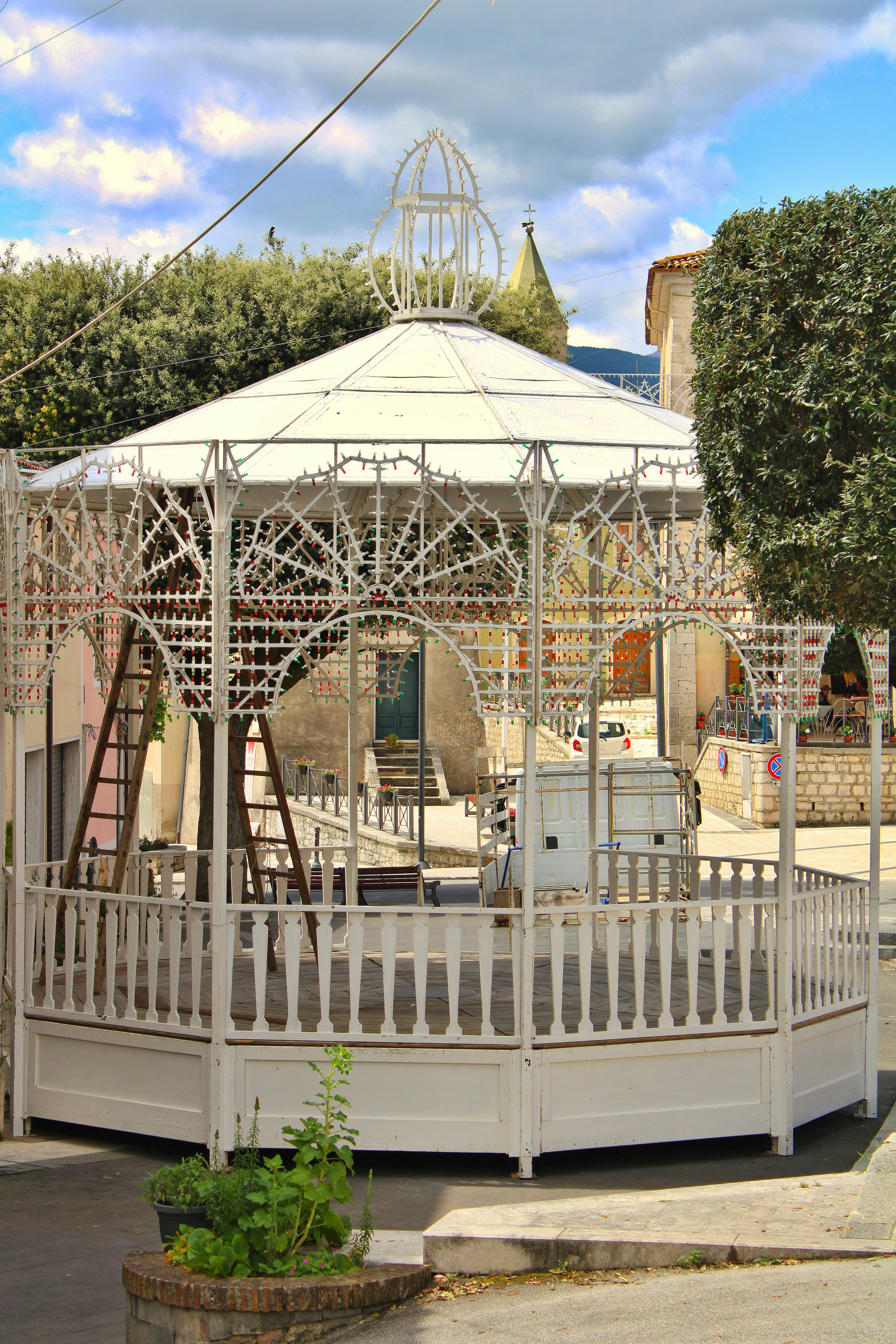 White ornate gazebo crowned with iron lattice under a bright sky