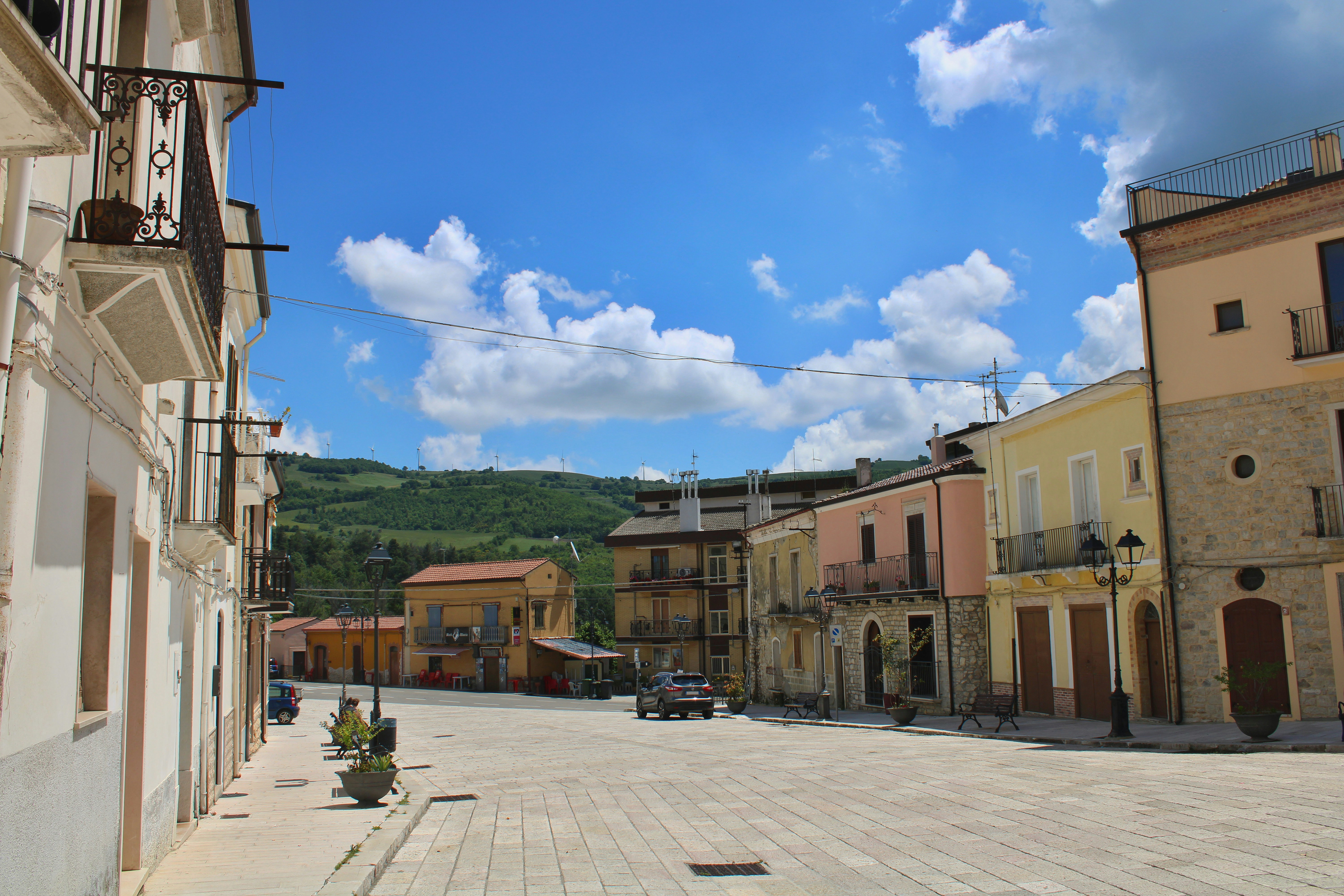 Sunlit Piazza Framed by pastel facades under a Serene Blue Sky