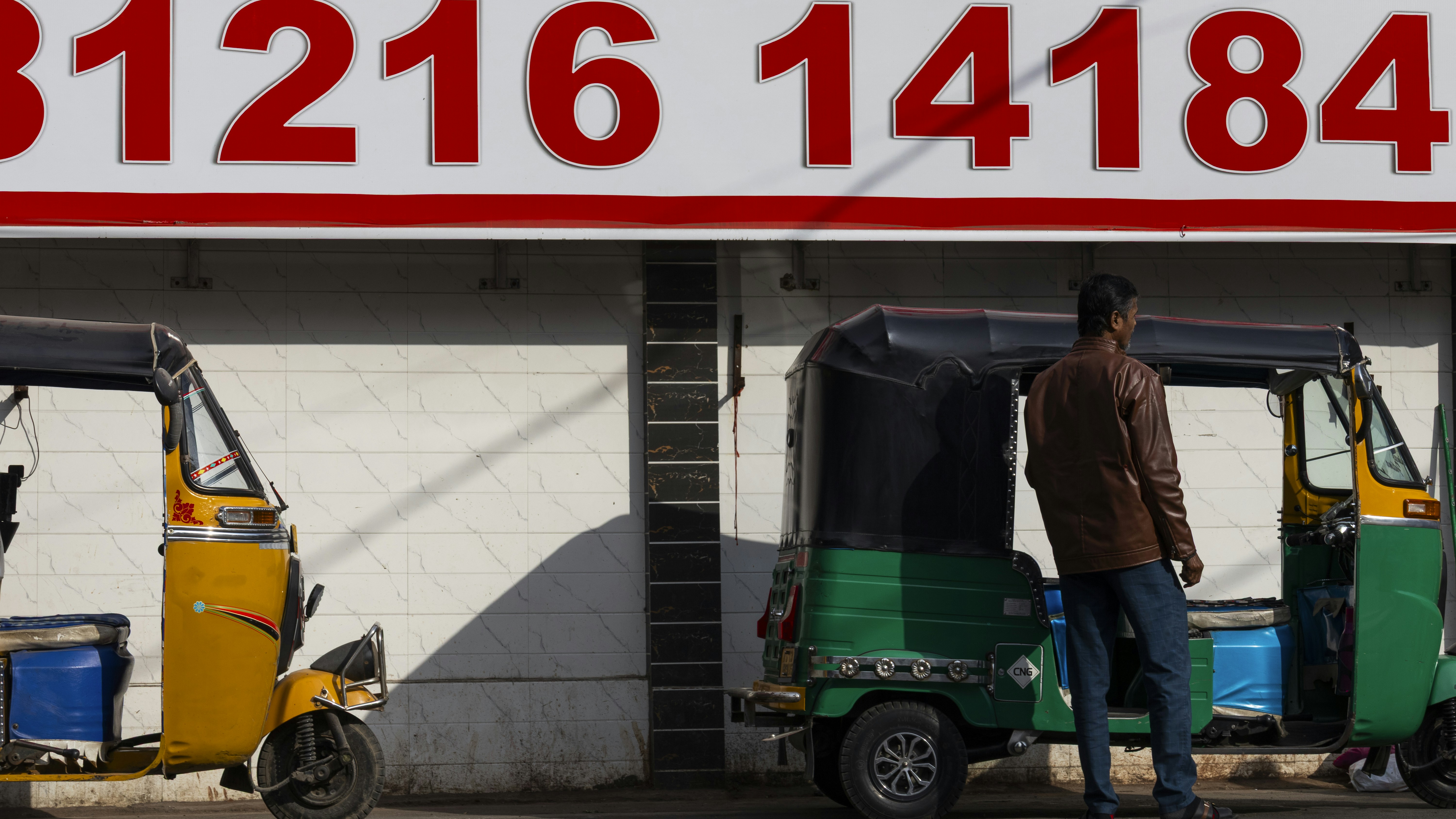 Behind the Red Numerals: Auto Rickshaws and a passerby