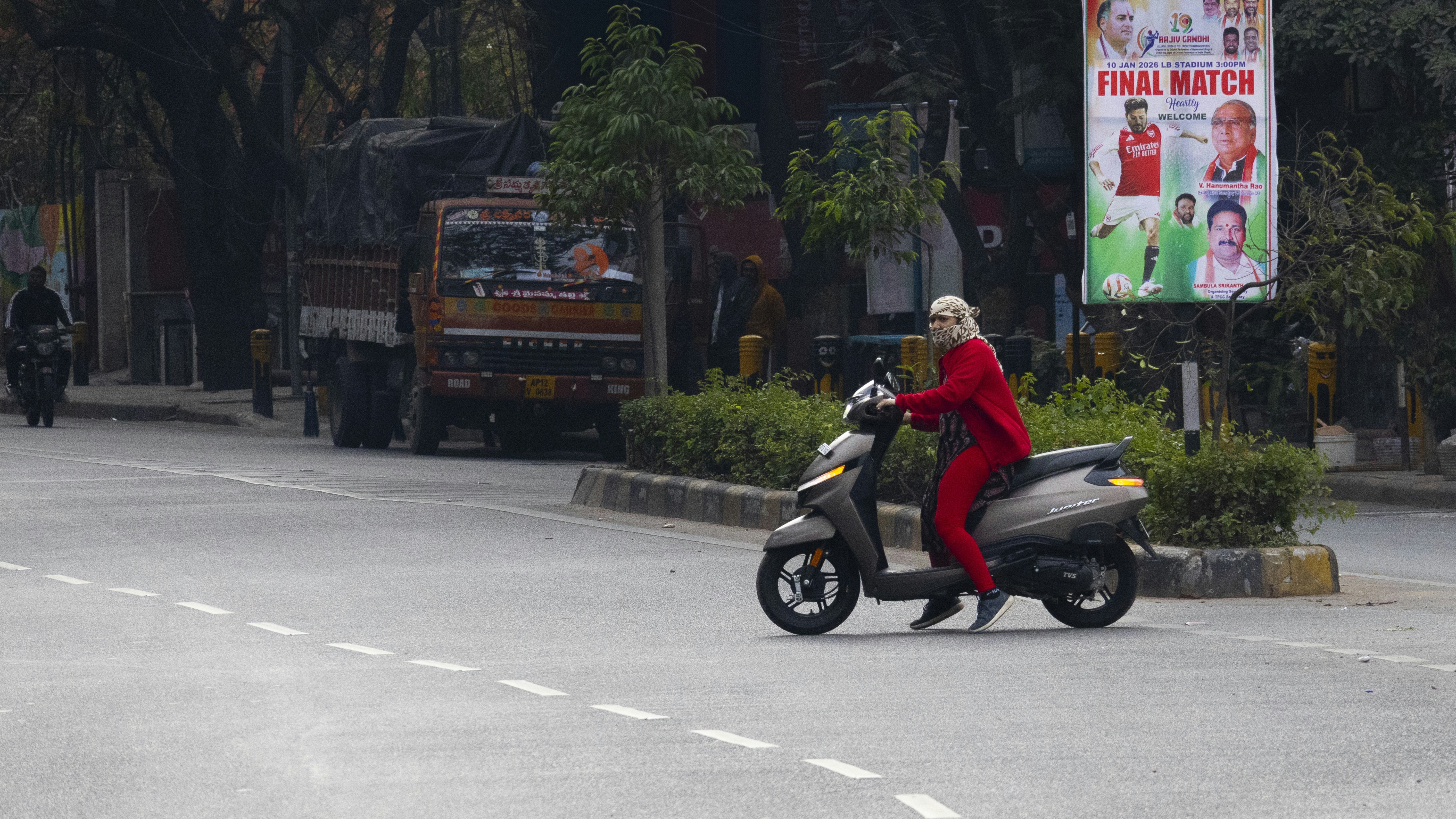 Red-clad rider crossing a quiet urban avenue