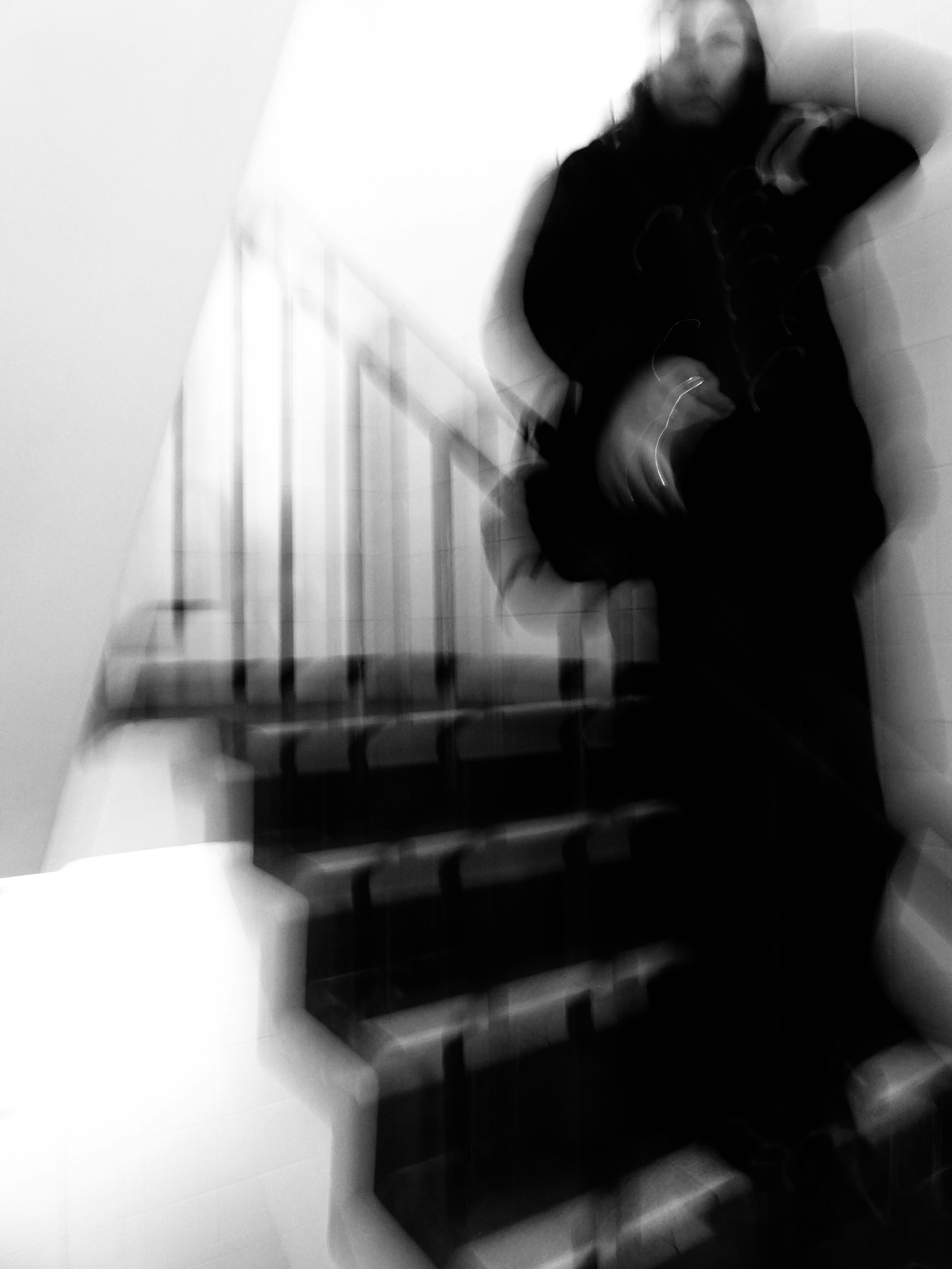 A blurry figure descends a staircase in darkness.