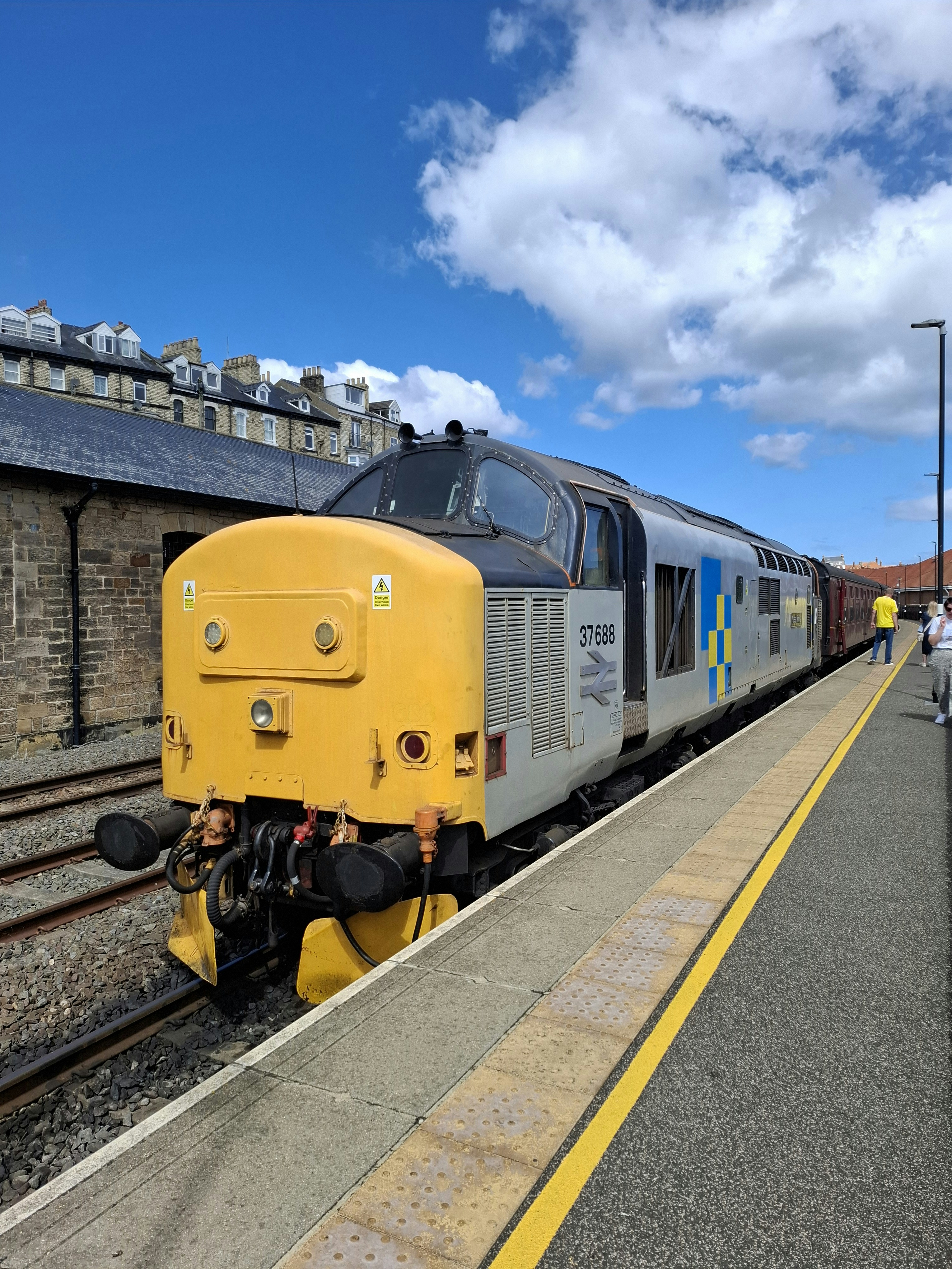 A yellow and grey train at a station platform.
