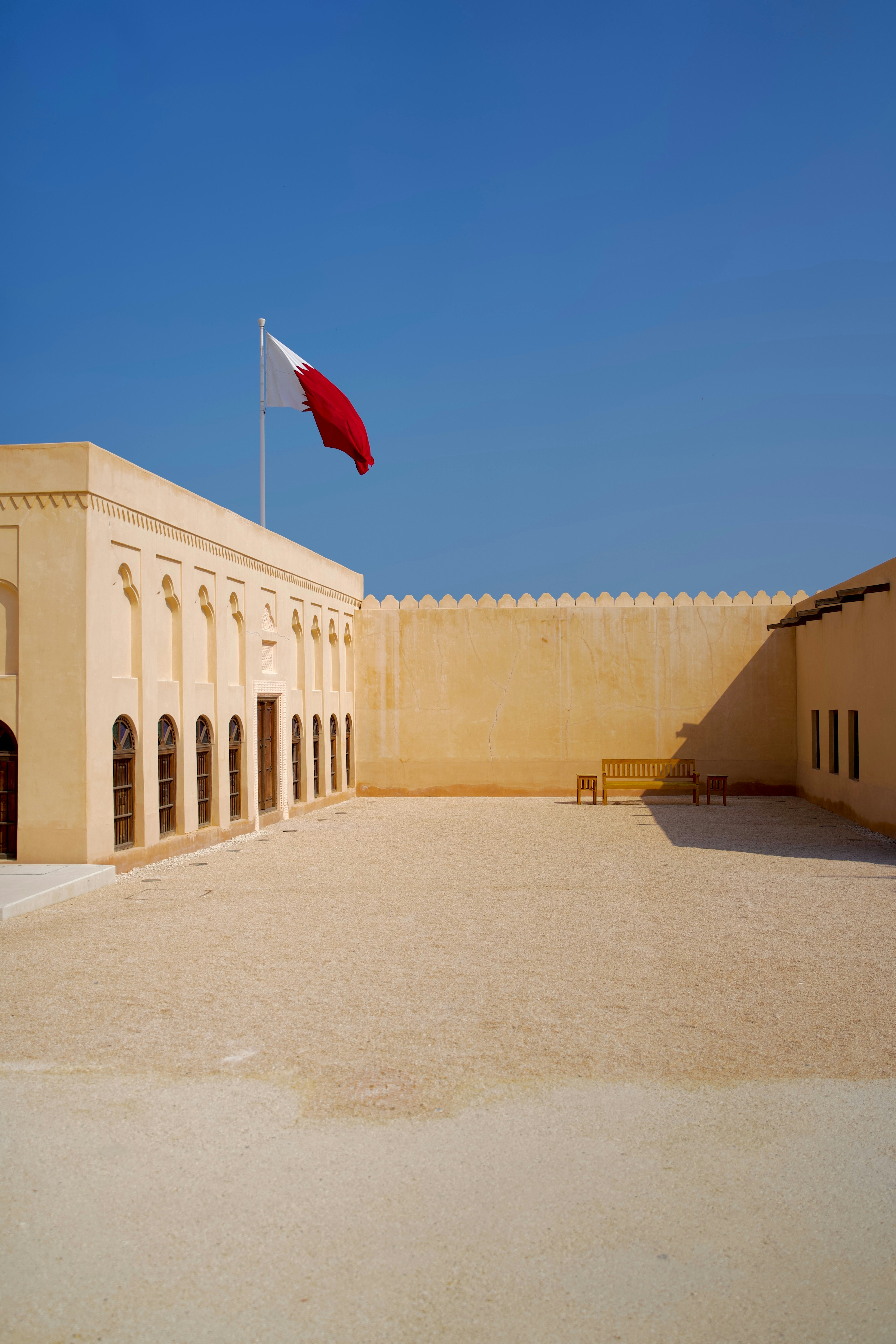 Flag over an ancient courtyard: sunlit arches and battlements