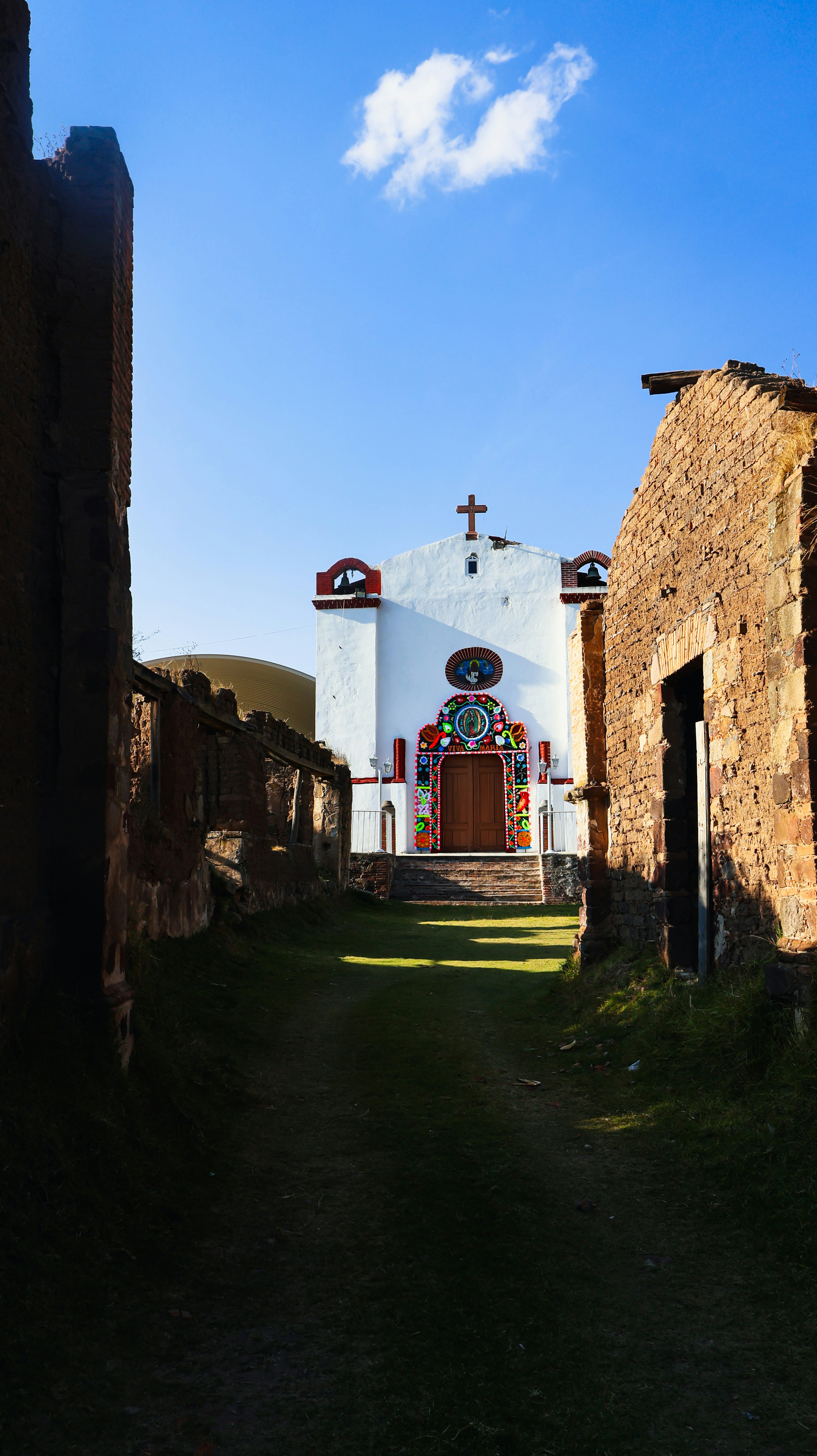 Sunlit Sanctuary: A White Chapel Framed by Shadowed Ruins