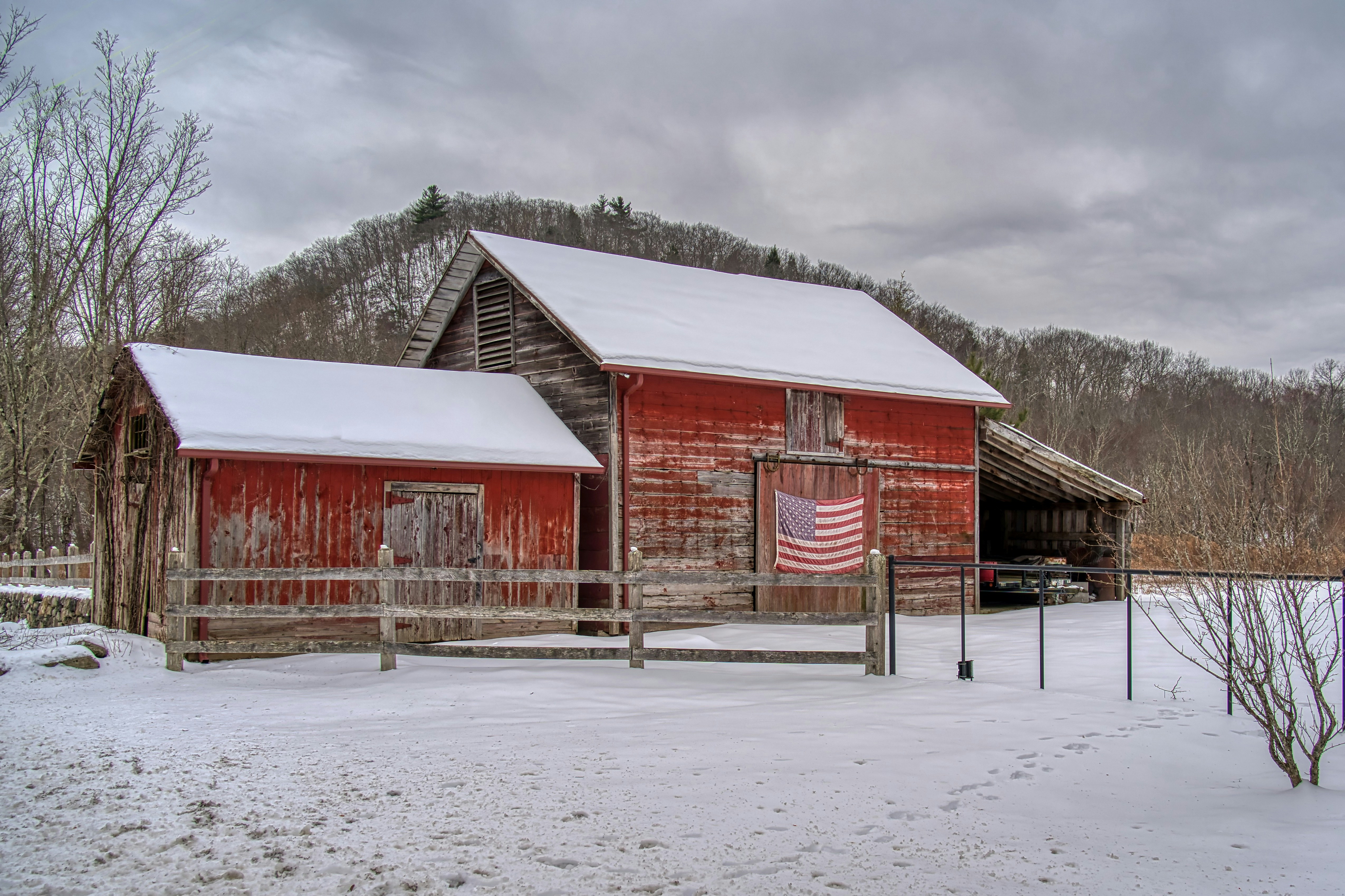 Red Barn in Silent Snow, American Flag Drifting Beneath an Overcast Sky